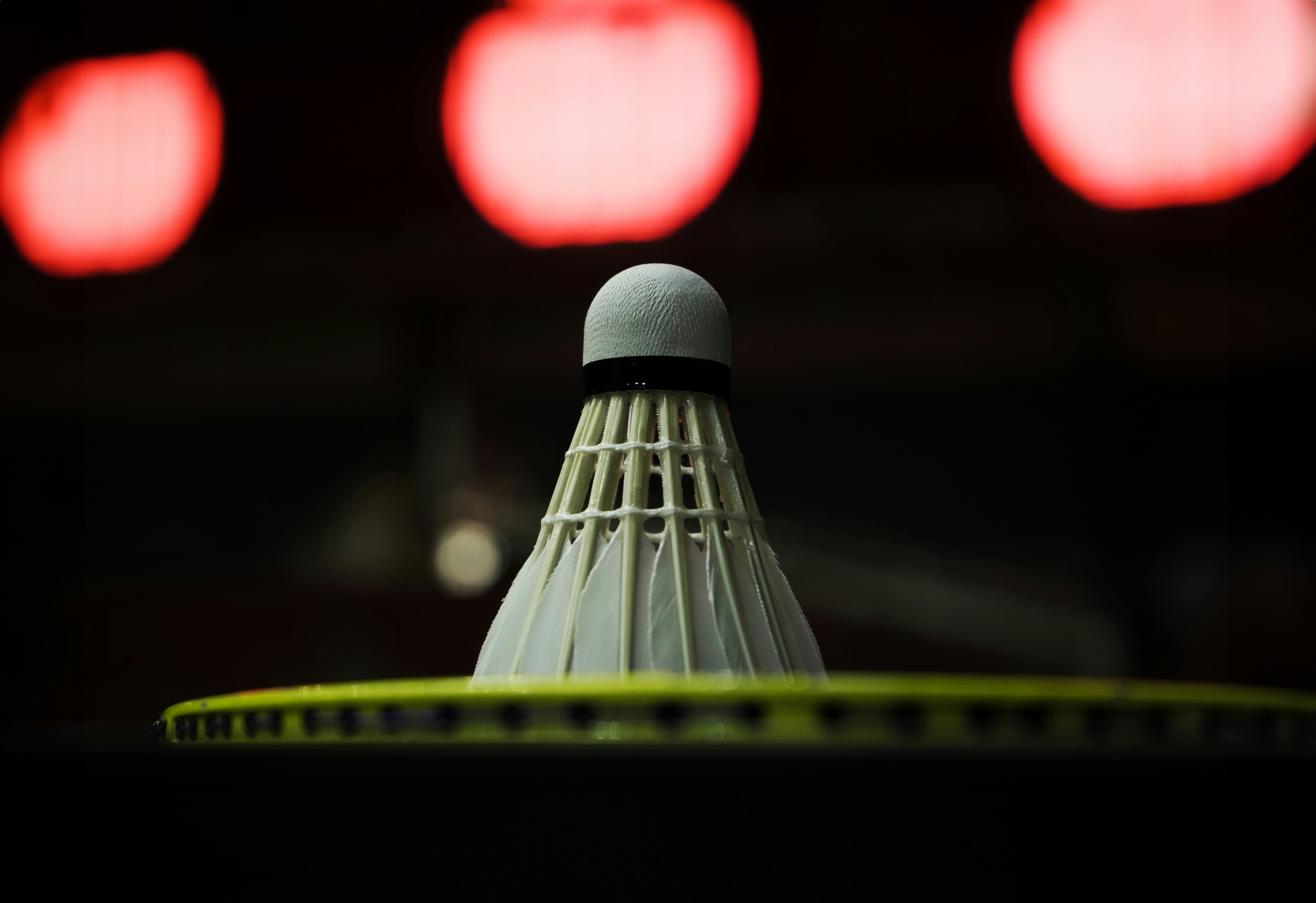 A close up of a badminton racket with red lights in the background ...