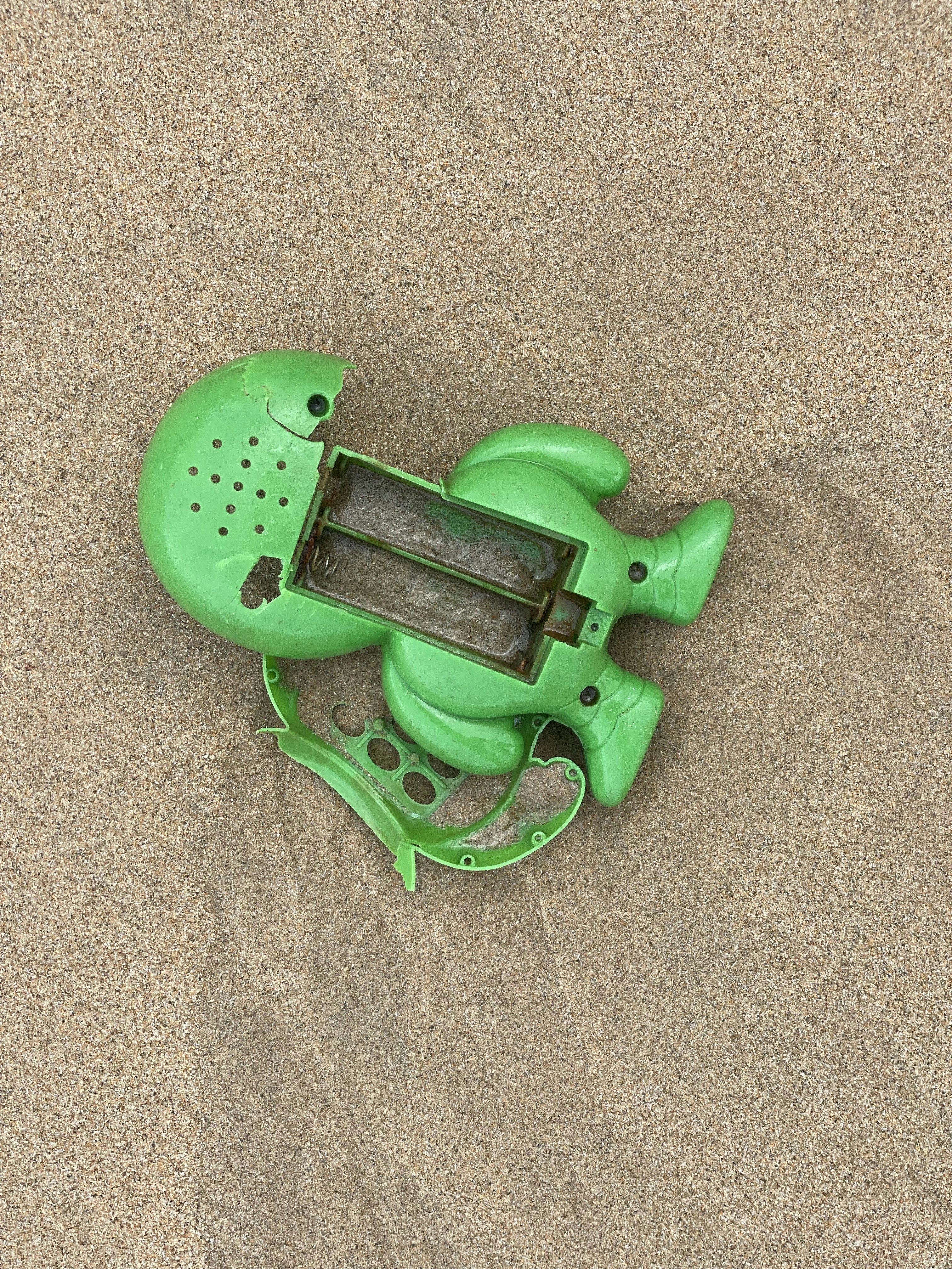 Emerald Desert Relic: A Green Gadget Half-Buried in Sand