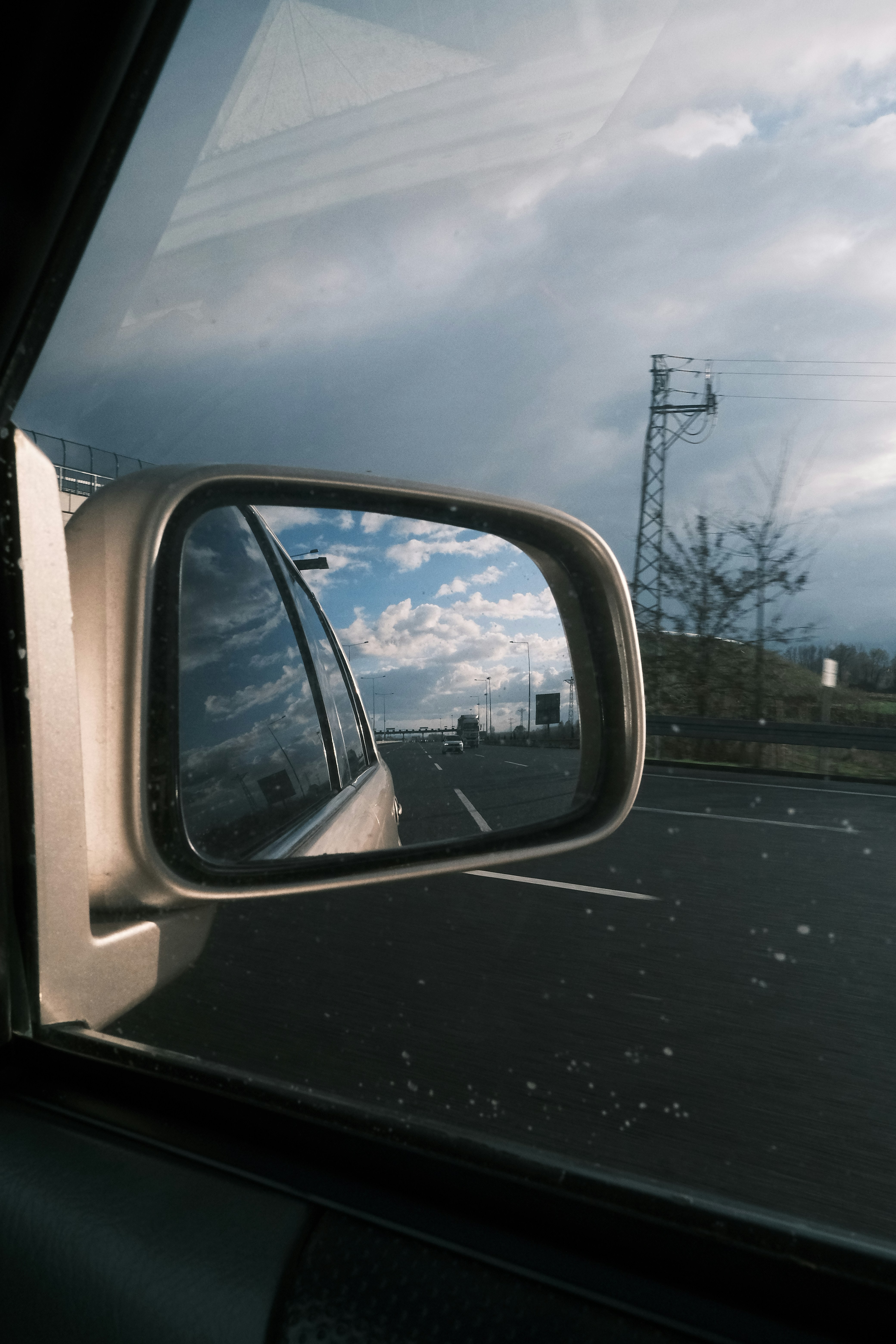 Rearview Mirage: Highway Vanishing Point in a Rain-Speckled Mirror