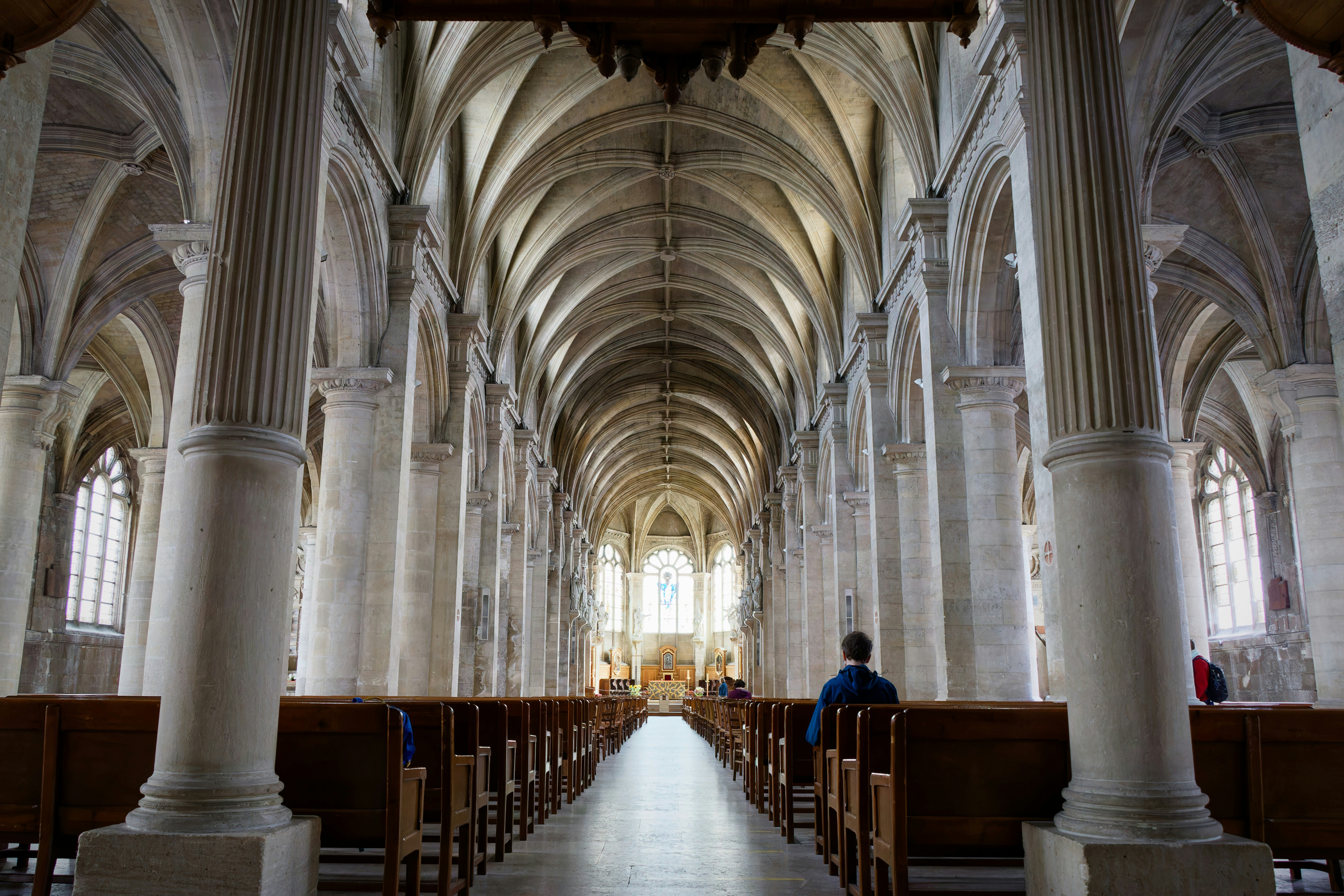 Gothic cathedral interior with soaring arches and light filtering through stained glass windows.