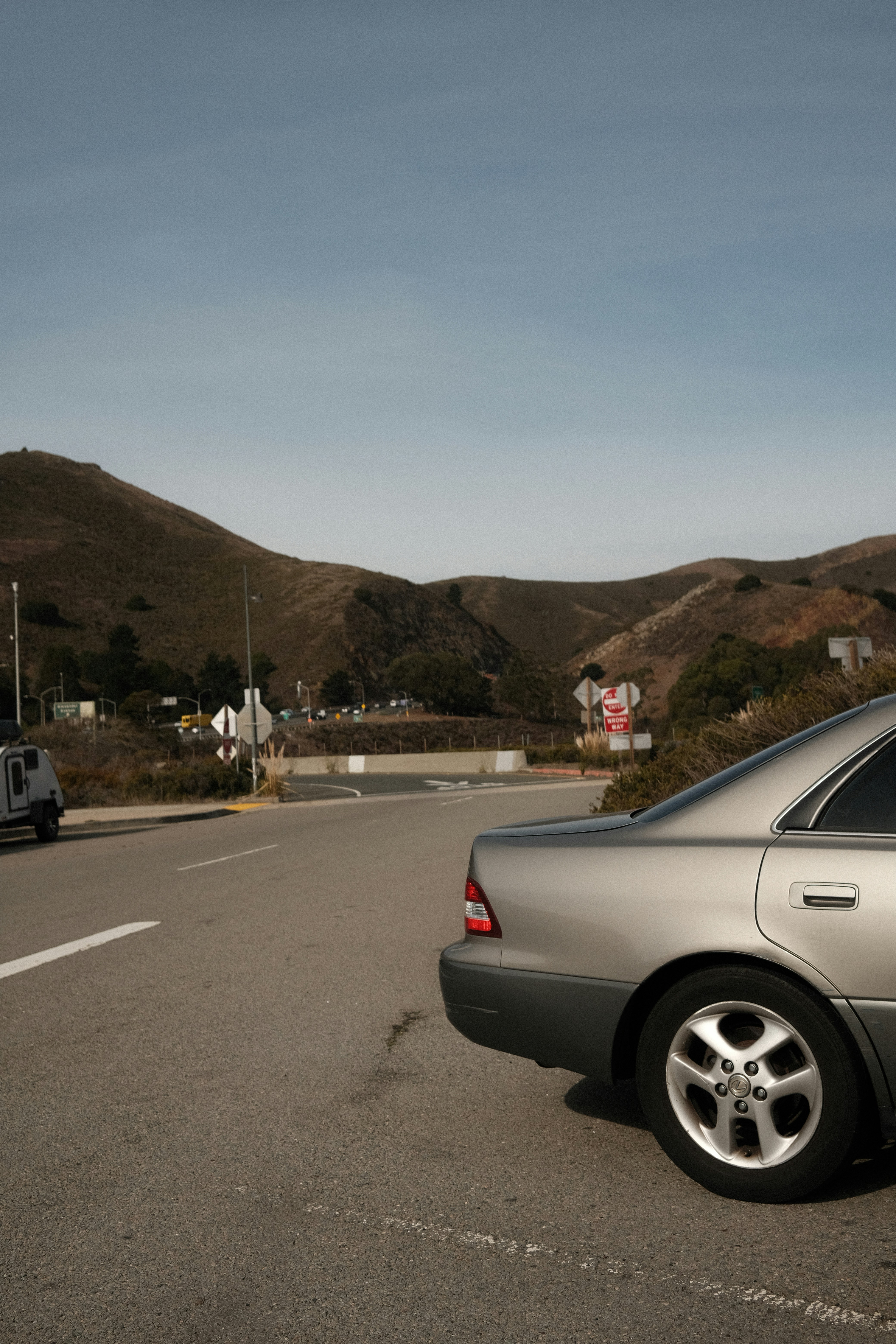 Rear-Quarter of a sedan against a hillside road scene