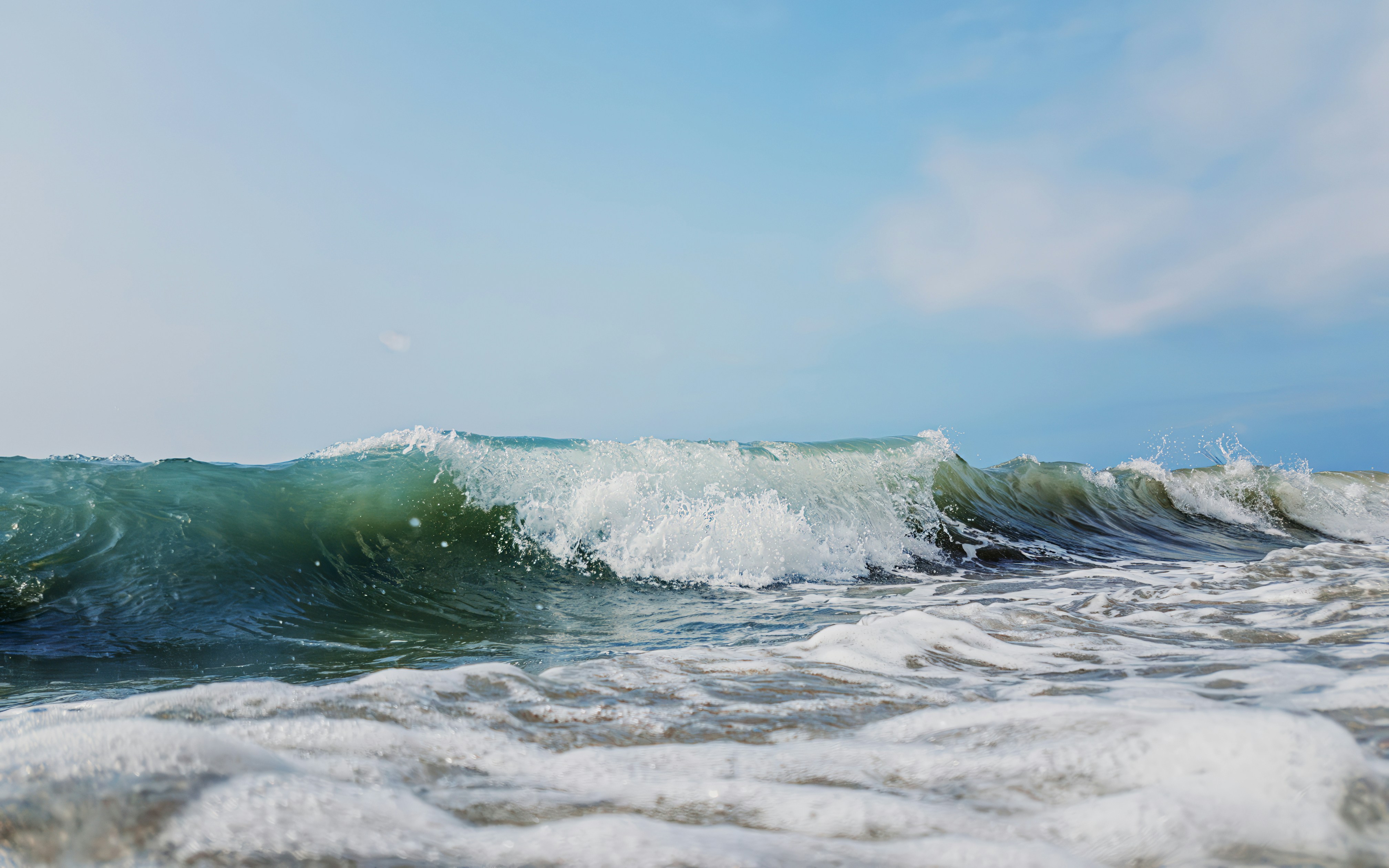A wave is breaking on a beach with a blue sky photo – Free Sea Image on ...