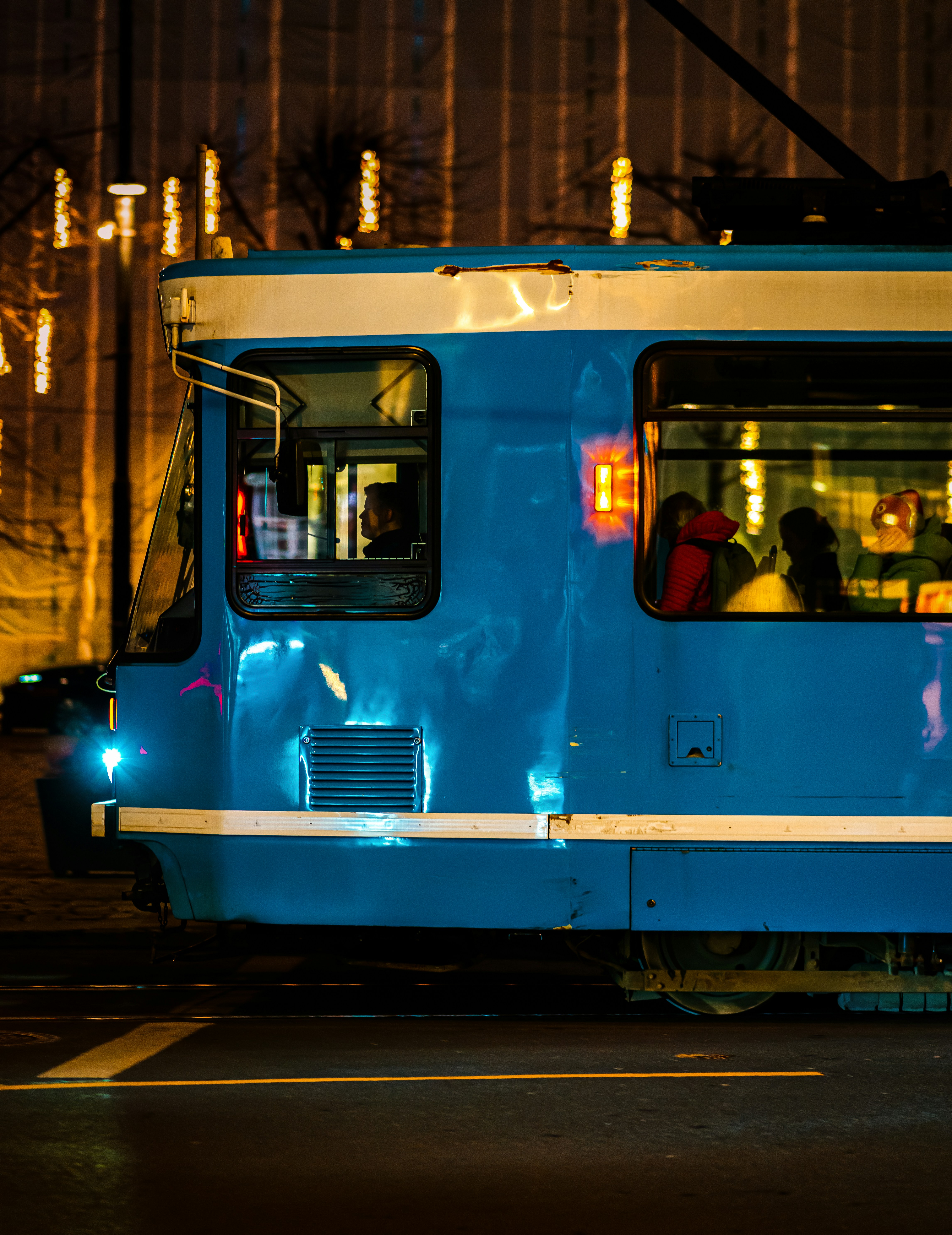 Midnight-Blue Tram: Warm Window Glows in a Neon Night