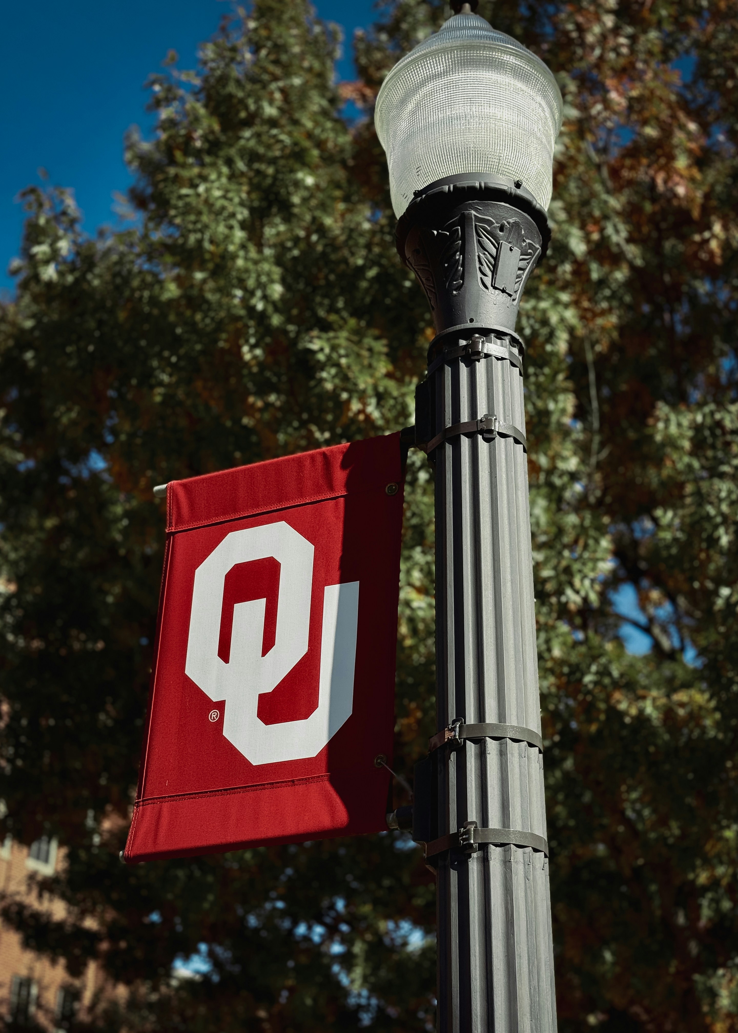 Crimson OU Banner Draped on a Classic Streetlamp Under a Clear Blue Sky