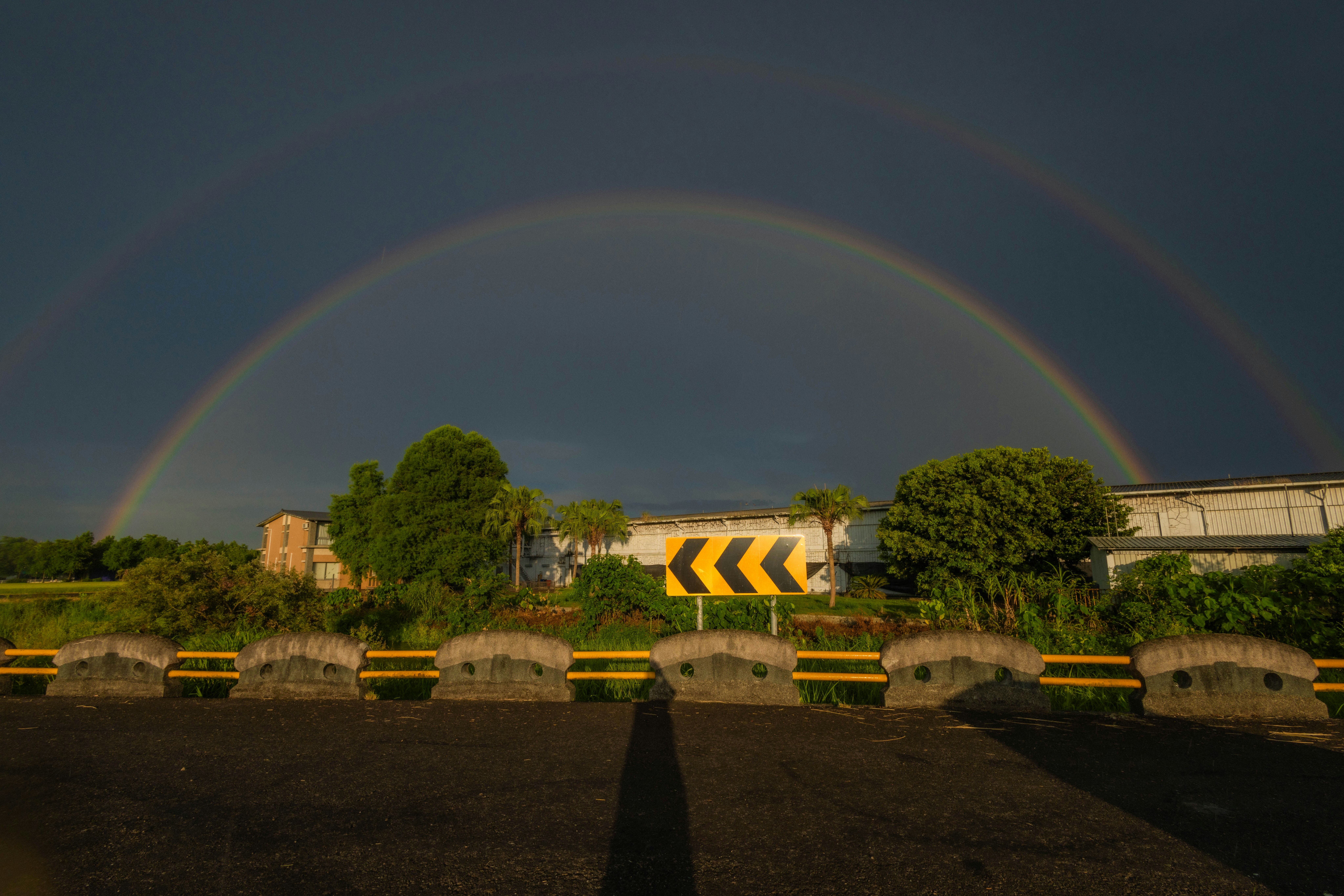 Twin Rainbows Over a Quiet Highway Barrier
