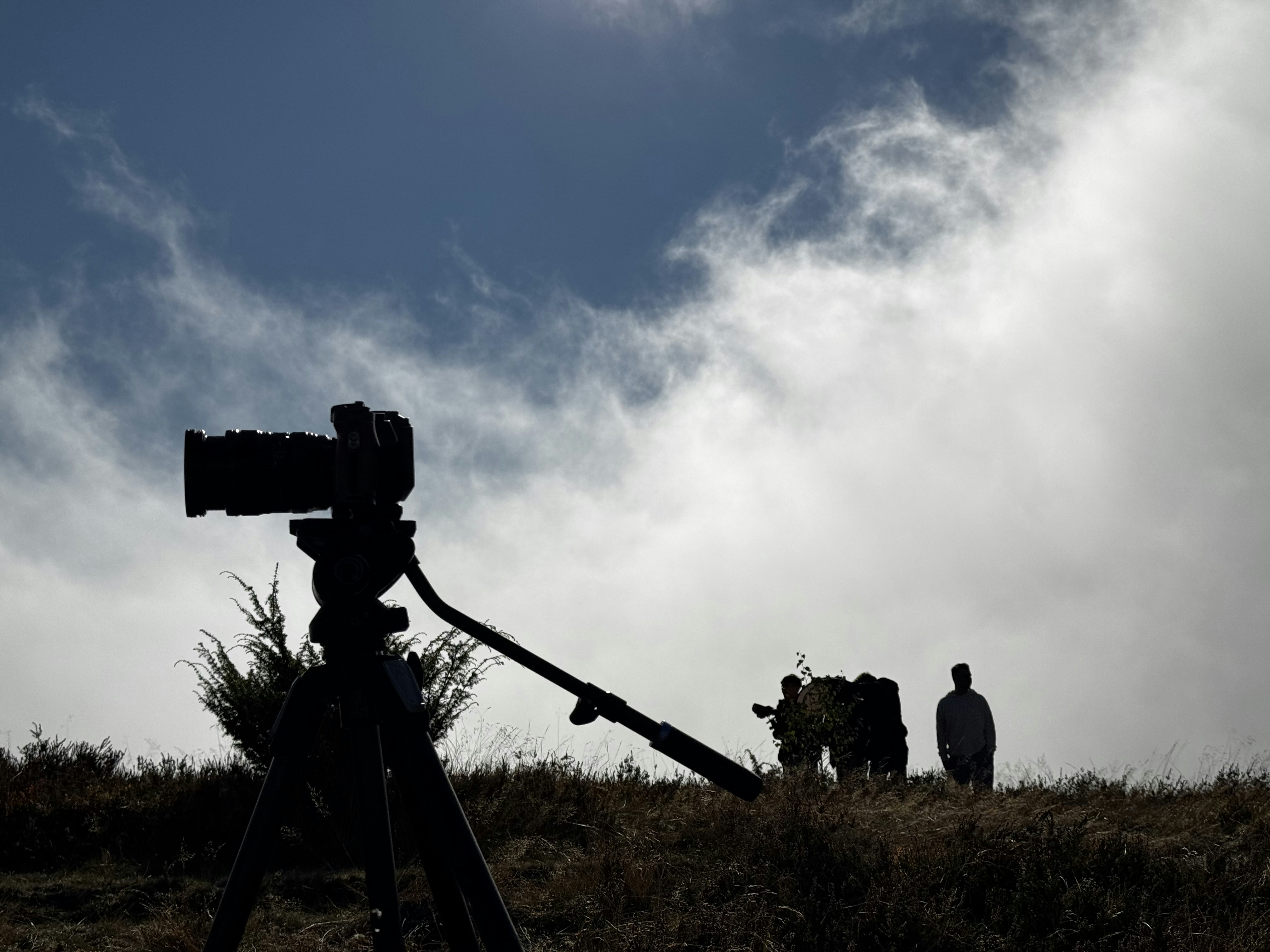 Hilltop Silhouette: A Giant Lens Overlook on a Cloudy Sky