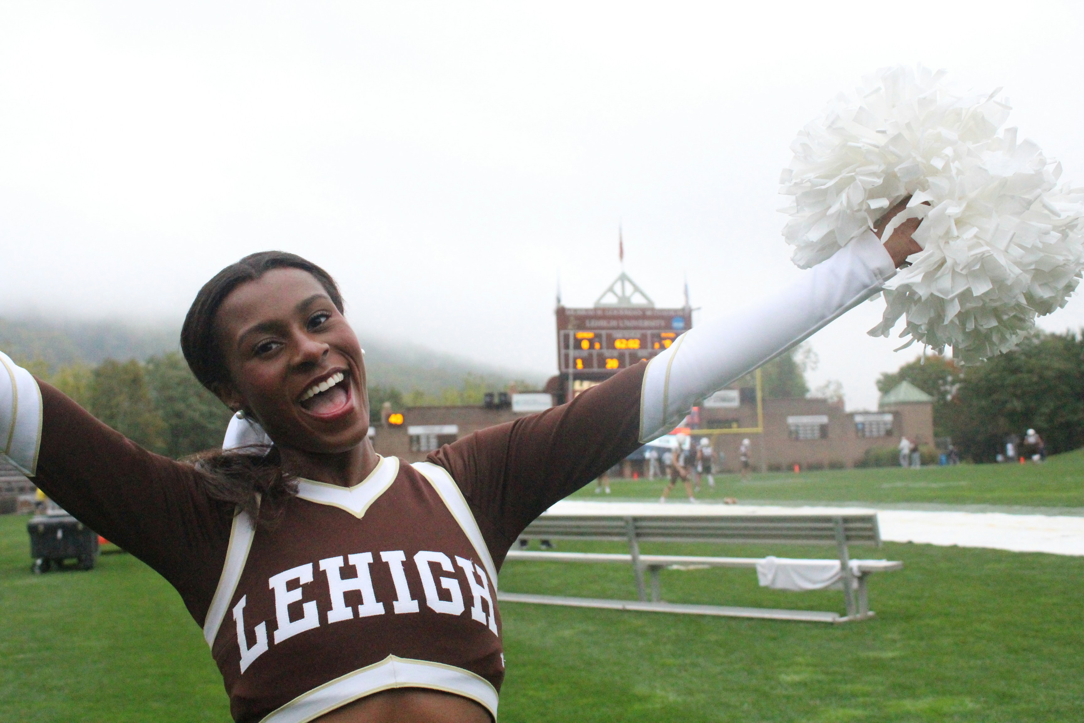 A cheerleader in a brown and white uniform holding a pom - pom photo ...