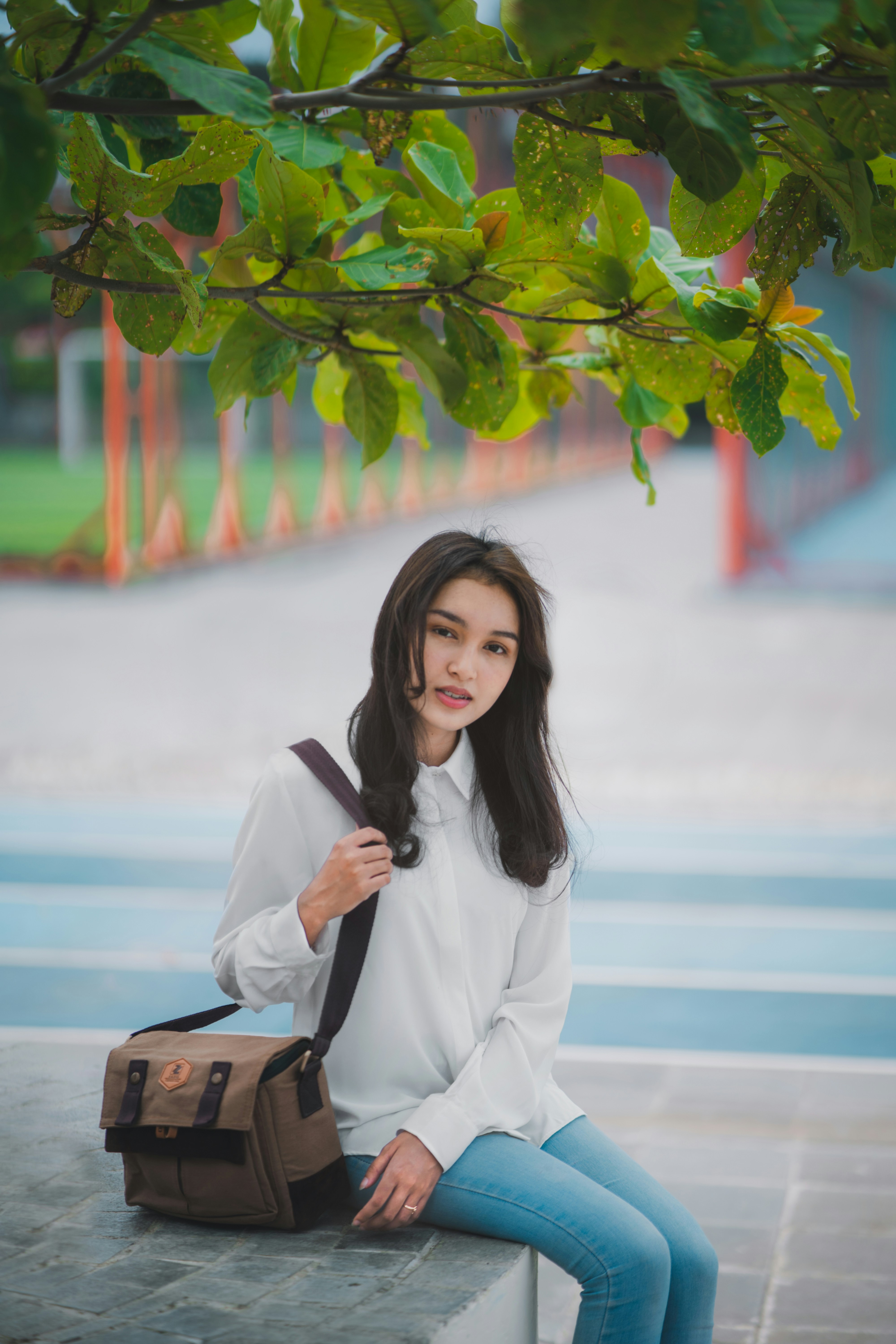 A woman sitting on a bench with a purse photo – Free Payakumbuh Image ...