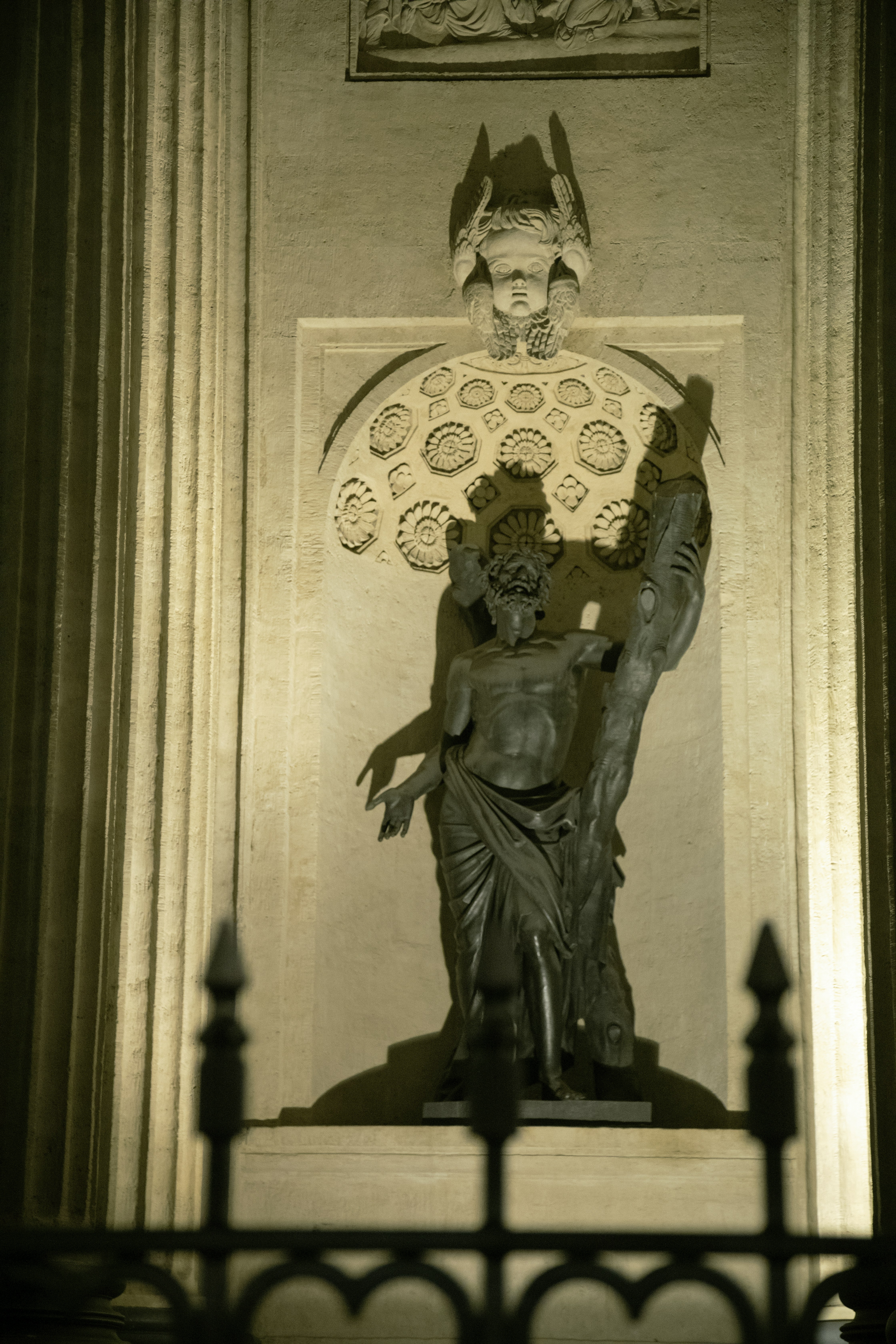 A statue of a man holding a frisbee in front of a buildingBelov Sergey