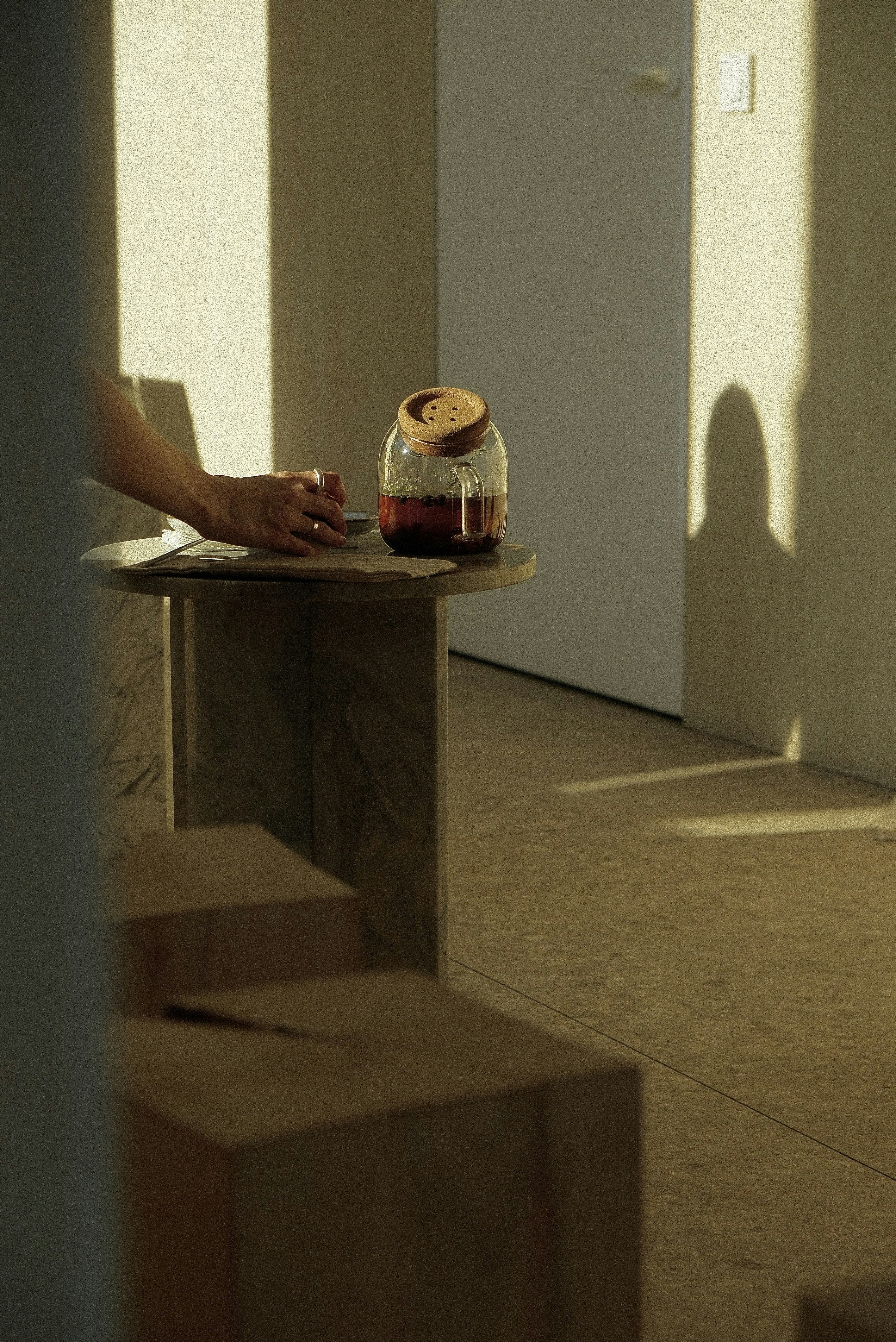 Amber Vessel on Quiet Wood: A Solitary Hand in Sunlit Silence