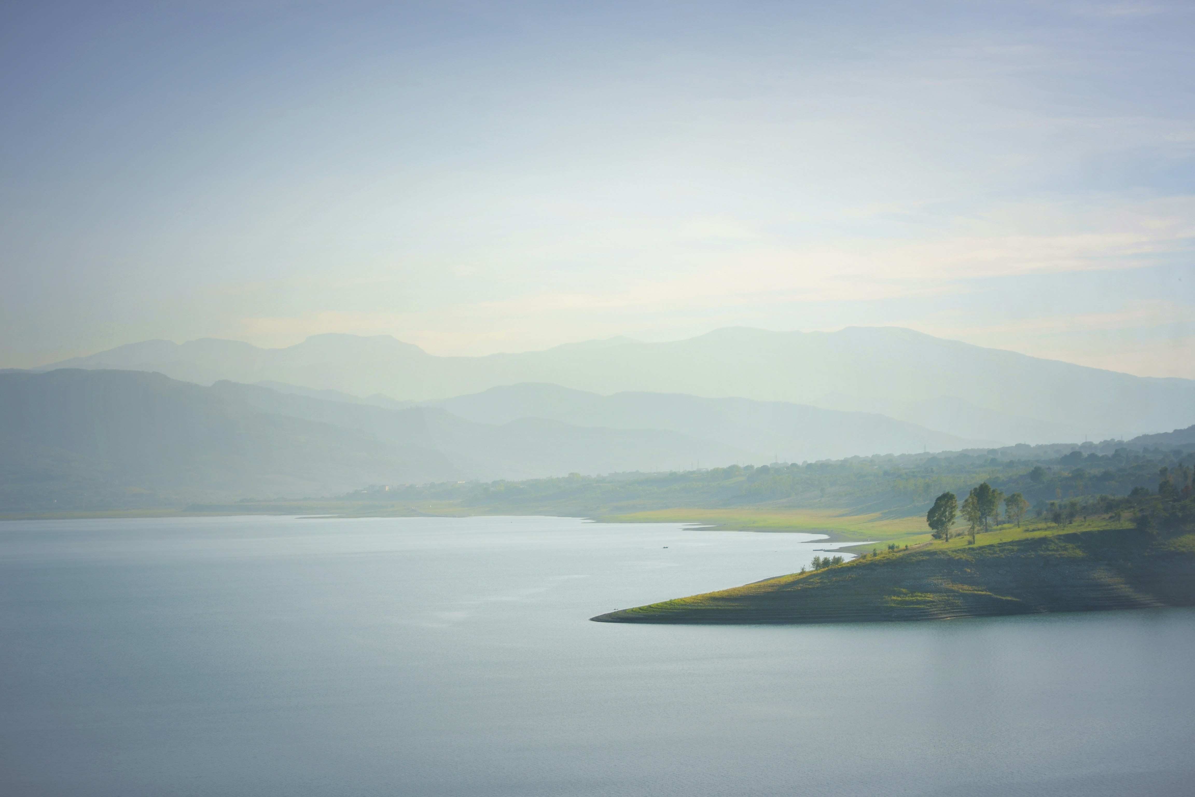 Soft morning light bathes the tranquil waters and distant hills of Senise Lake.