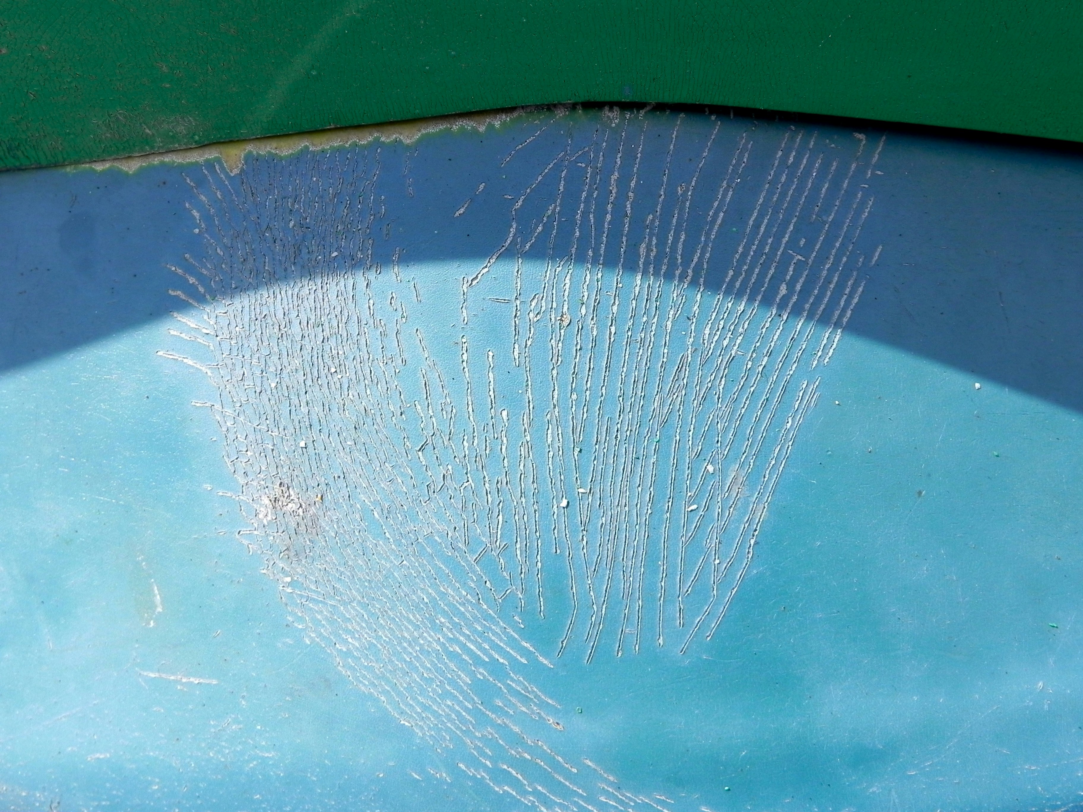 Blue panel with a curved green edge at top, featuring white scratch marks forming a wing-like pattern.
