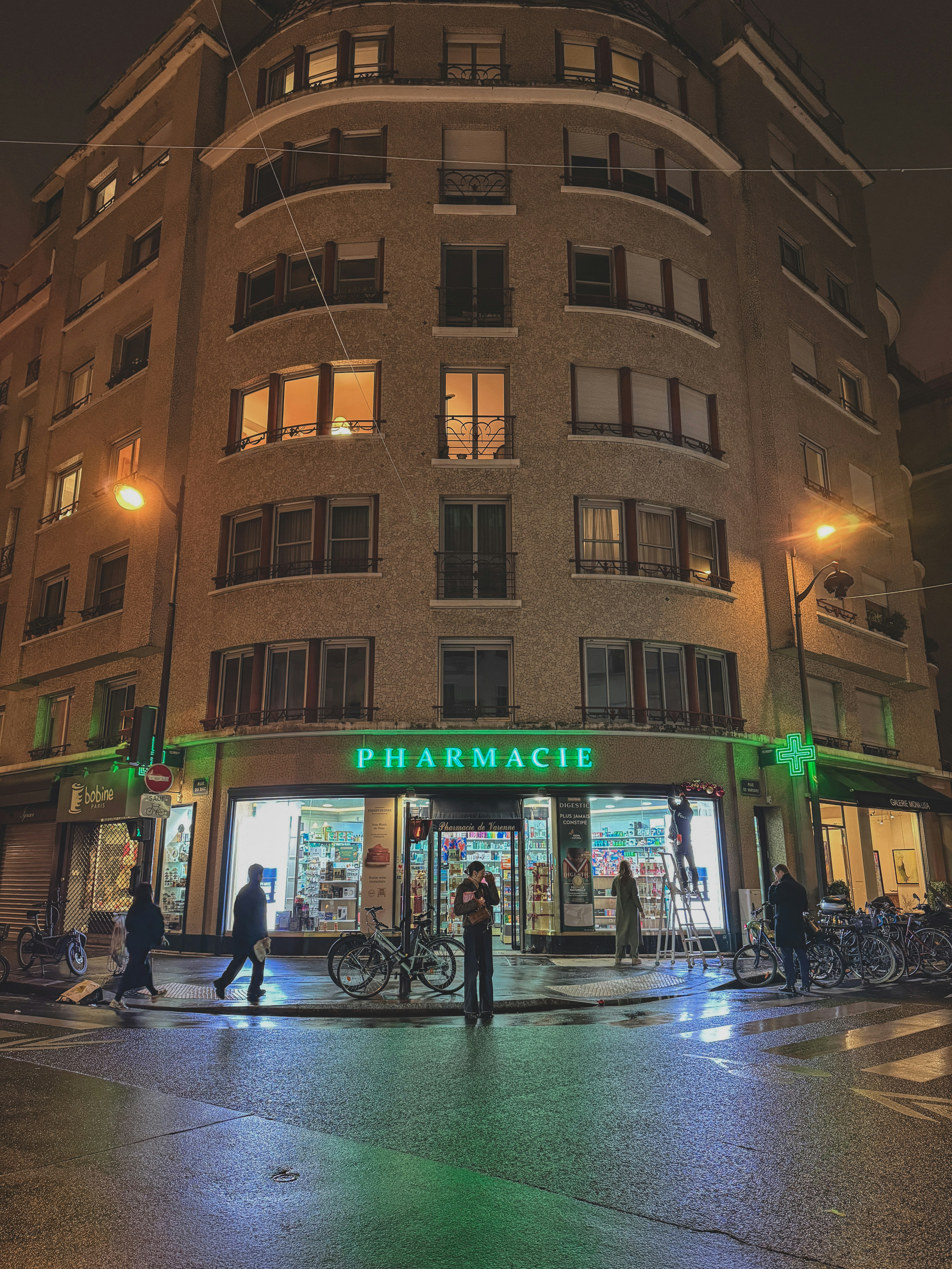 A street corner with a pharmacy store lit up at night photo – Free ...