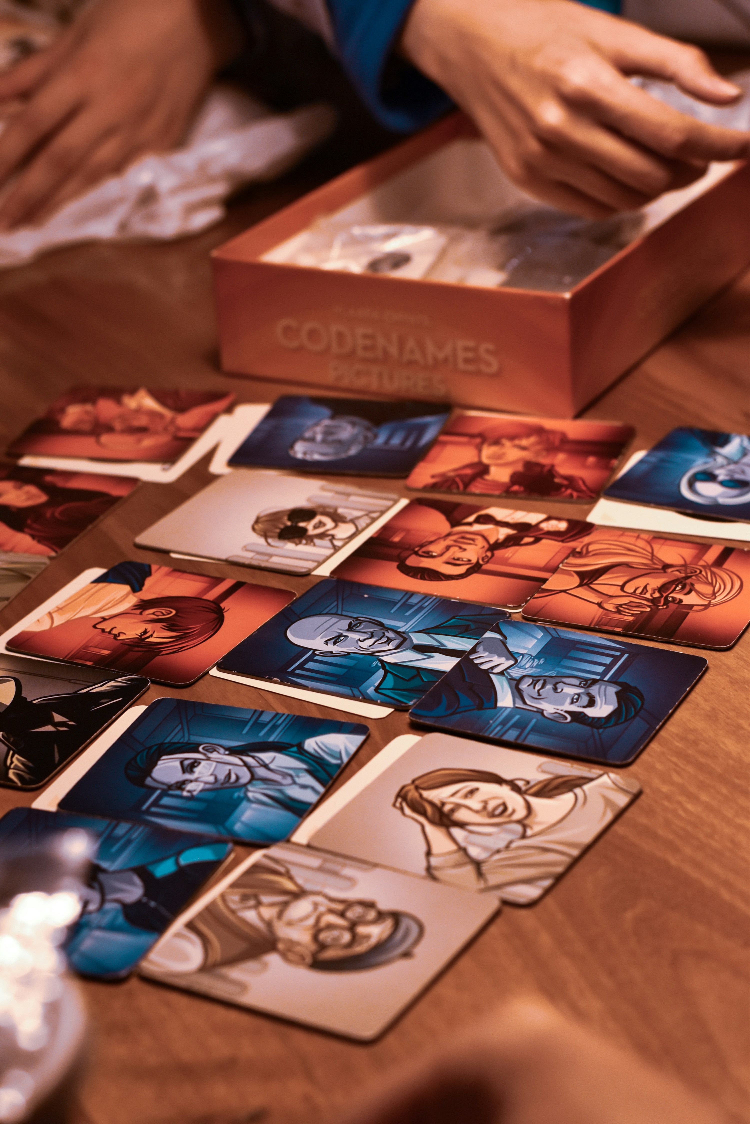 Cards Spread Across a Wooden Table with a Box of Codenames in the Background