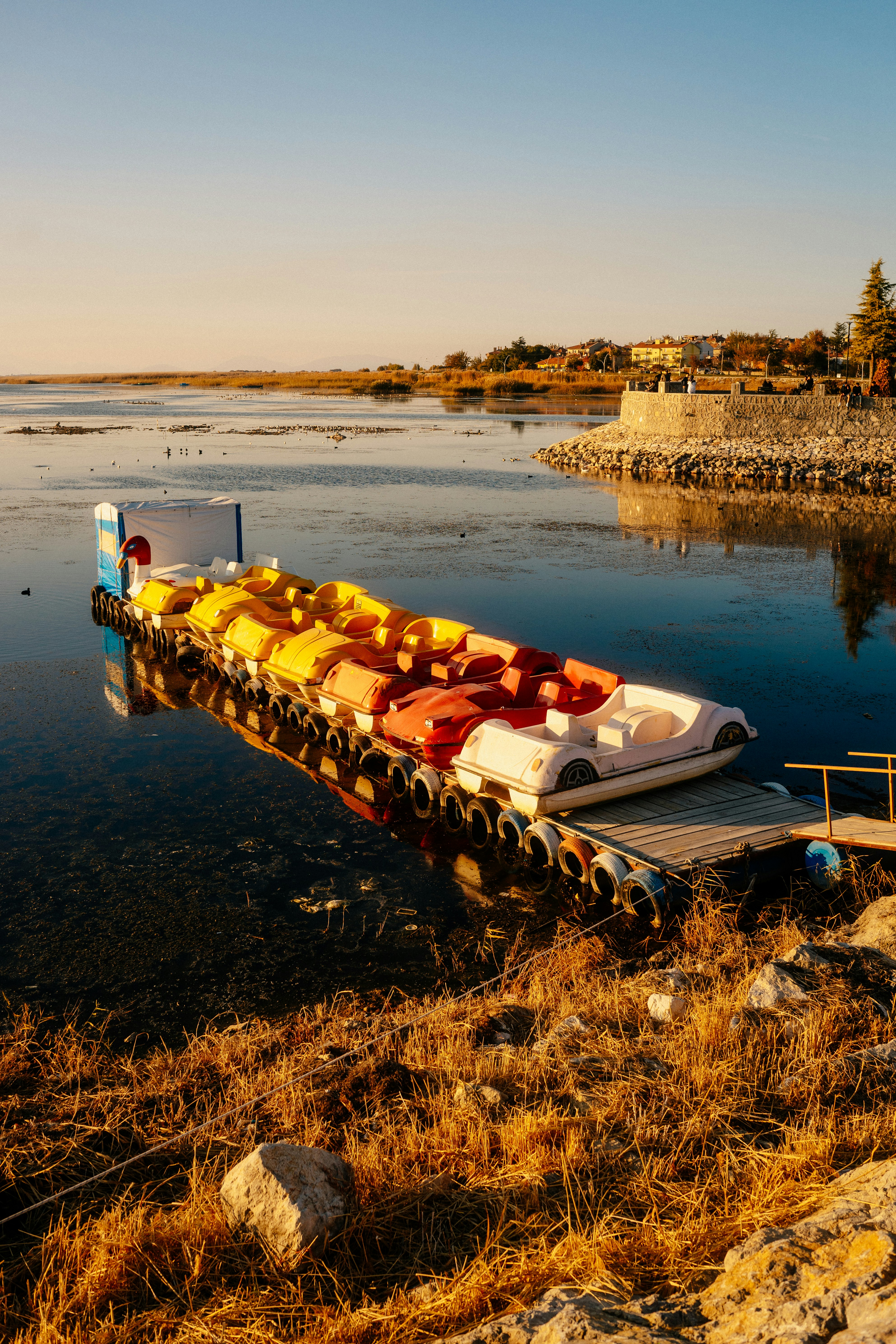 Golden Hour on the Dock: A Row of Paddle Boats in Sunset Colors