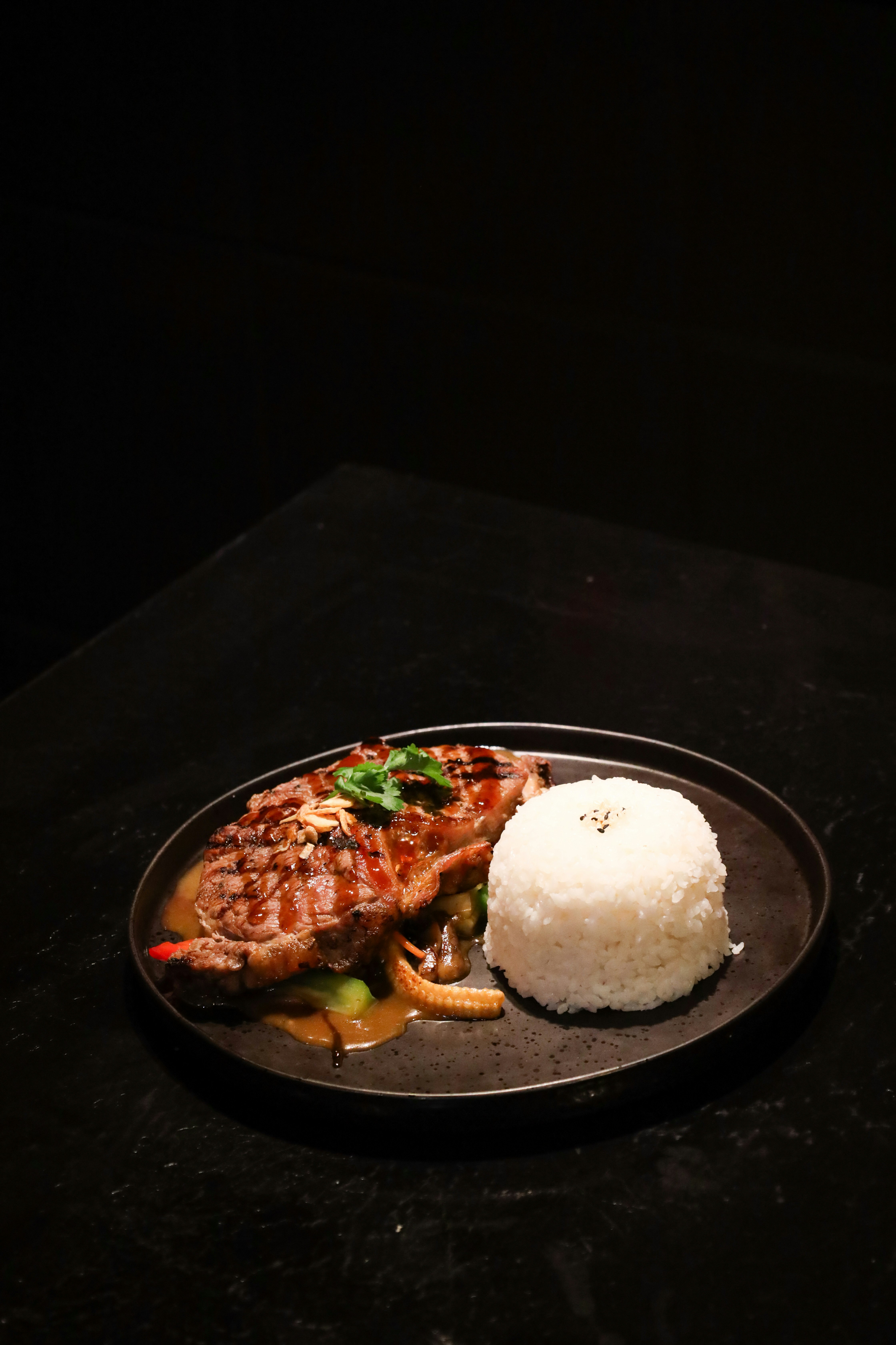 Charred Steak and a Rice Dome on a Velvet Black Plate
