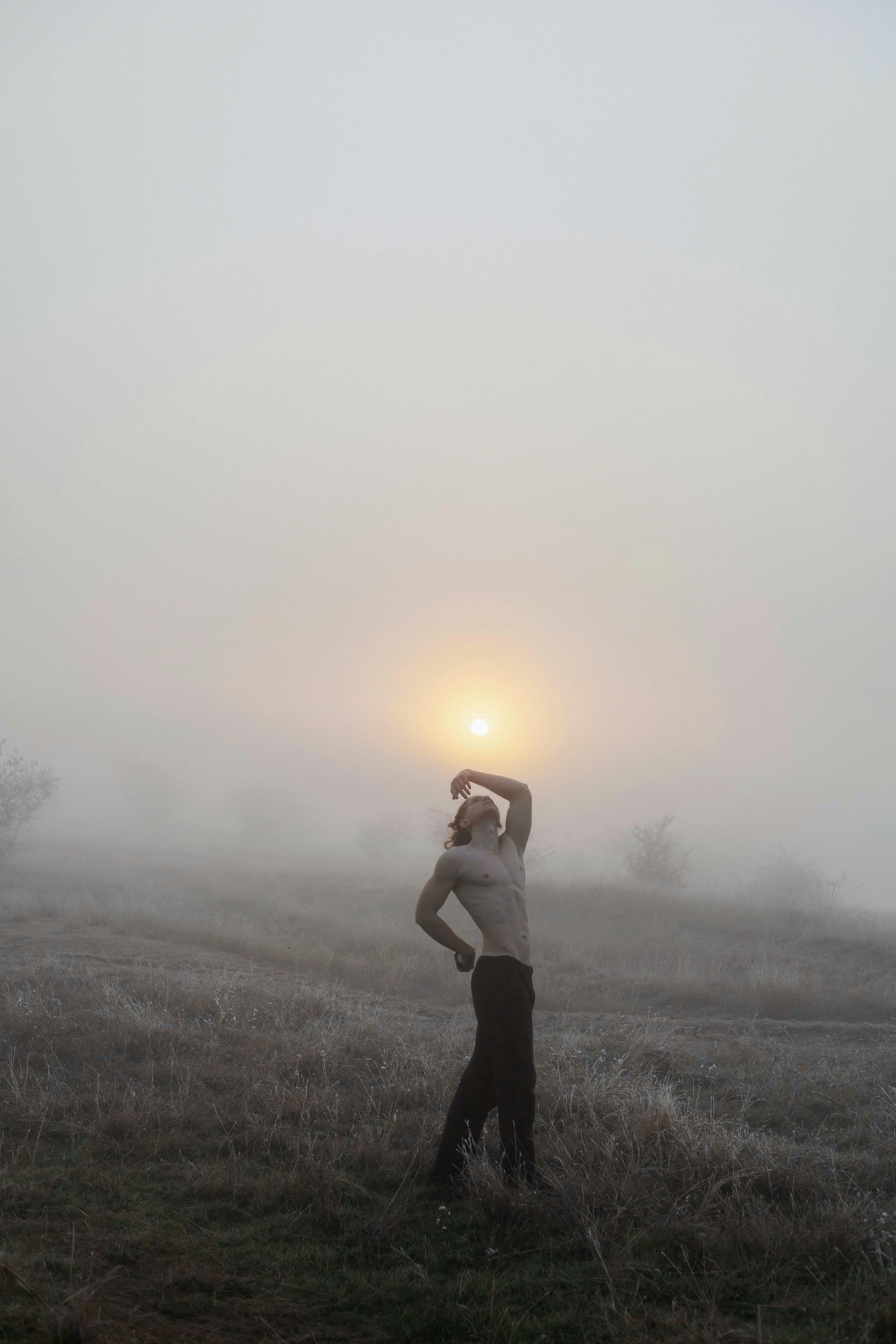 Dawn Silhouette in Mist: A Dancer Reaches Toward the Soft Sun