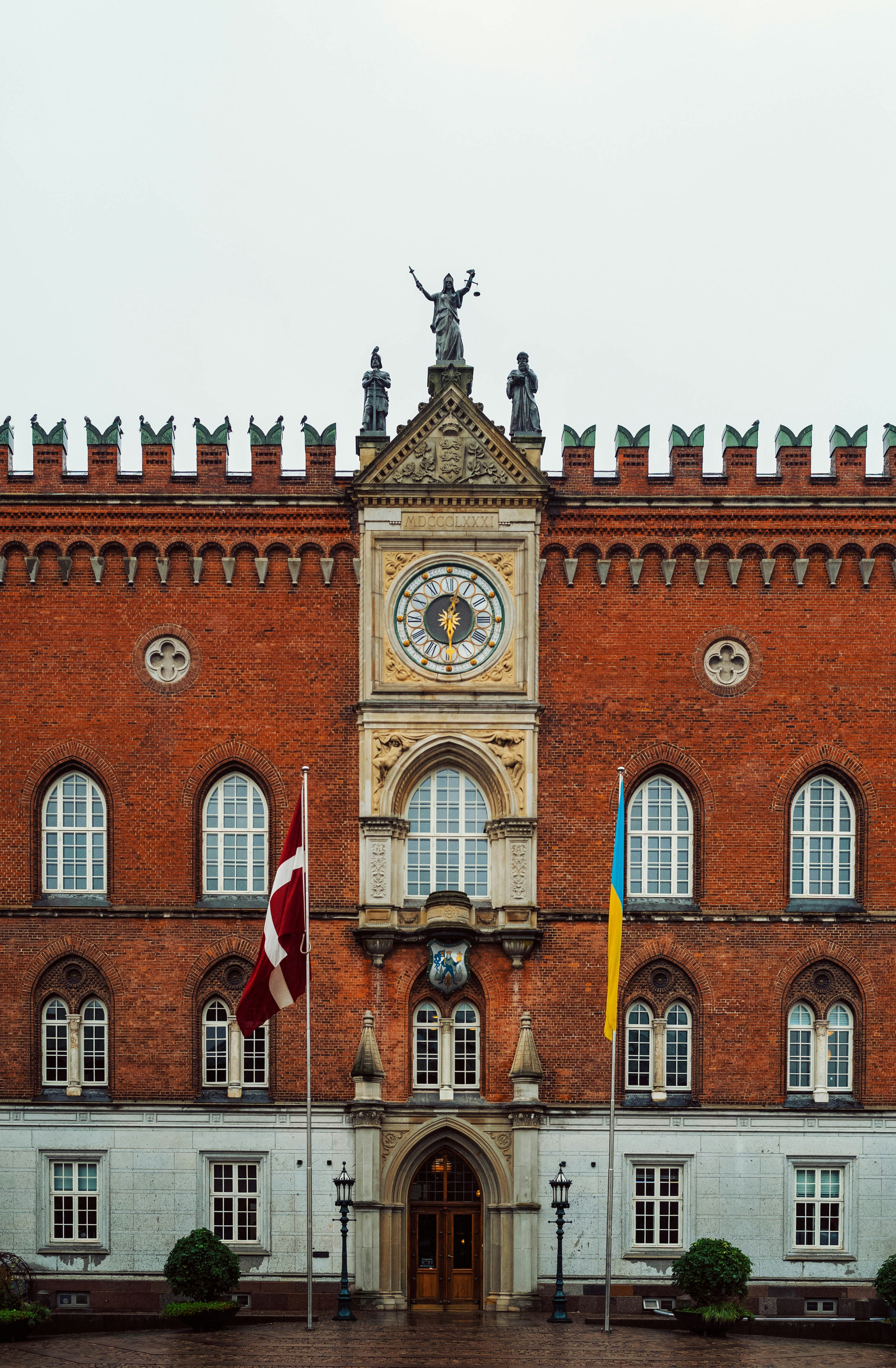 Clock Tower Crowned by Statues on a Nordic Red-Brick Facade