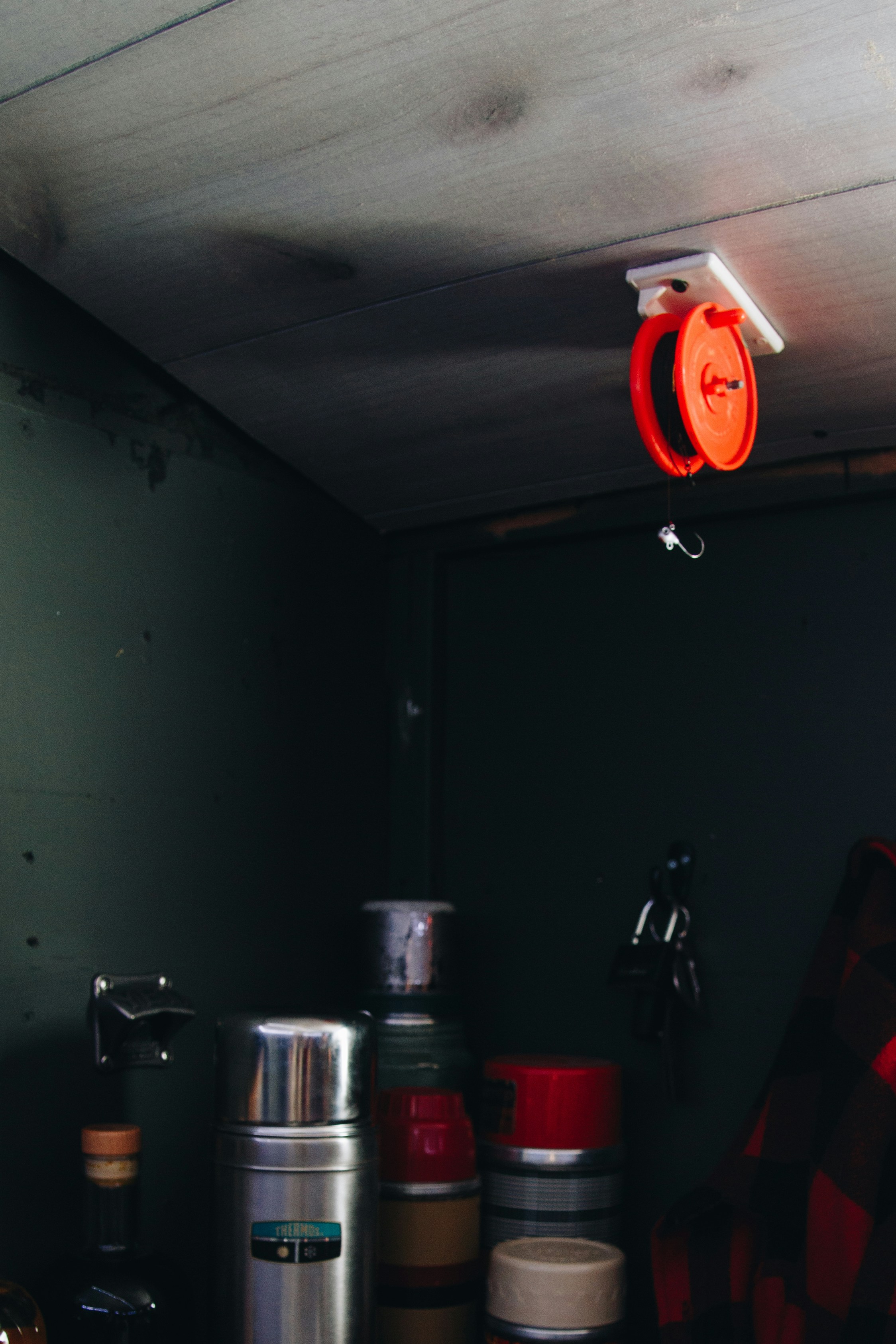 Red Ring Above the Tools: A Ceiling-Hung Safety Ring in a Dim Workshop