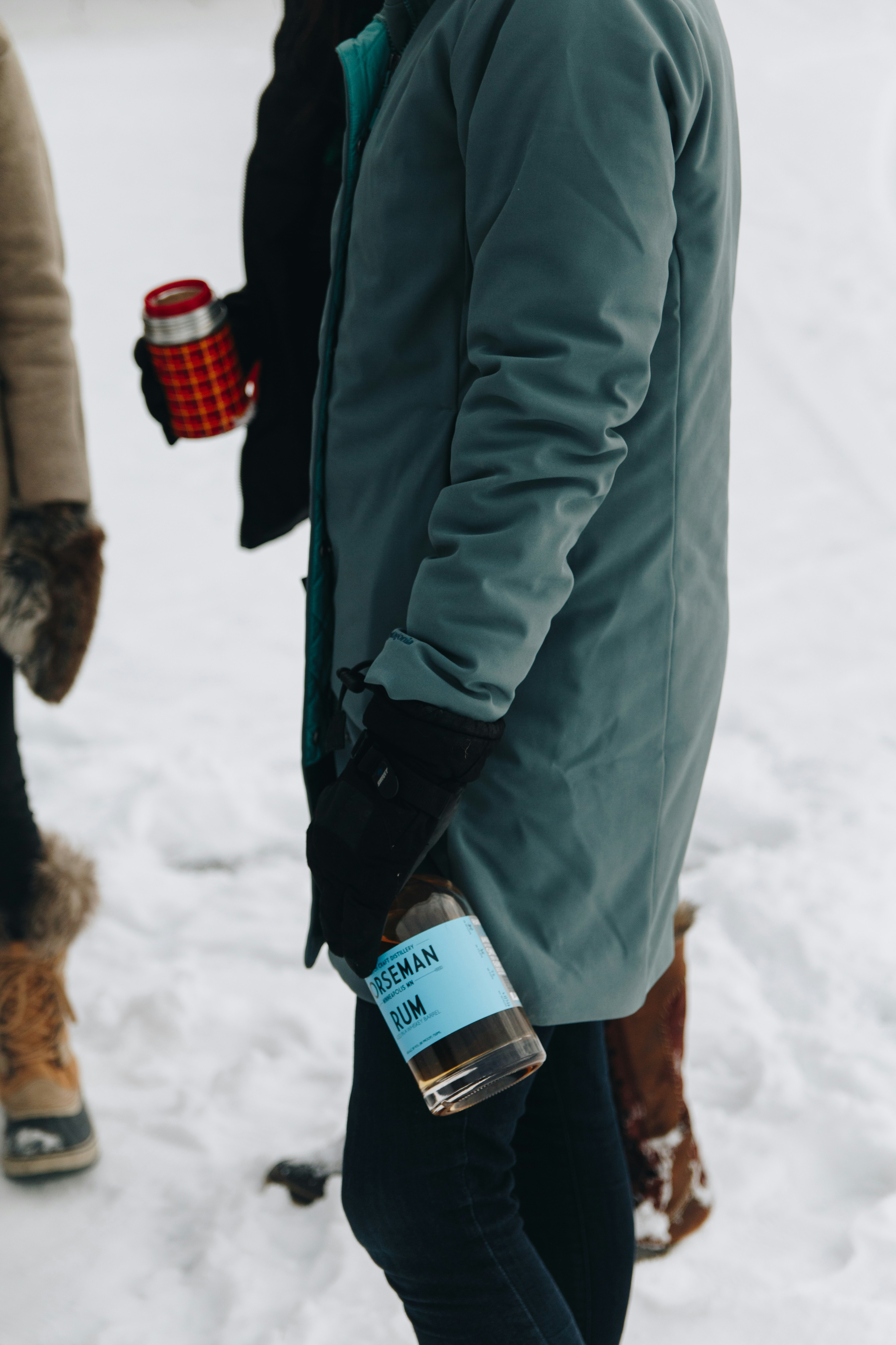 Teal Coat, Snow, and a Bottle: A Quiet Snow-Scene Moment