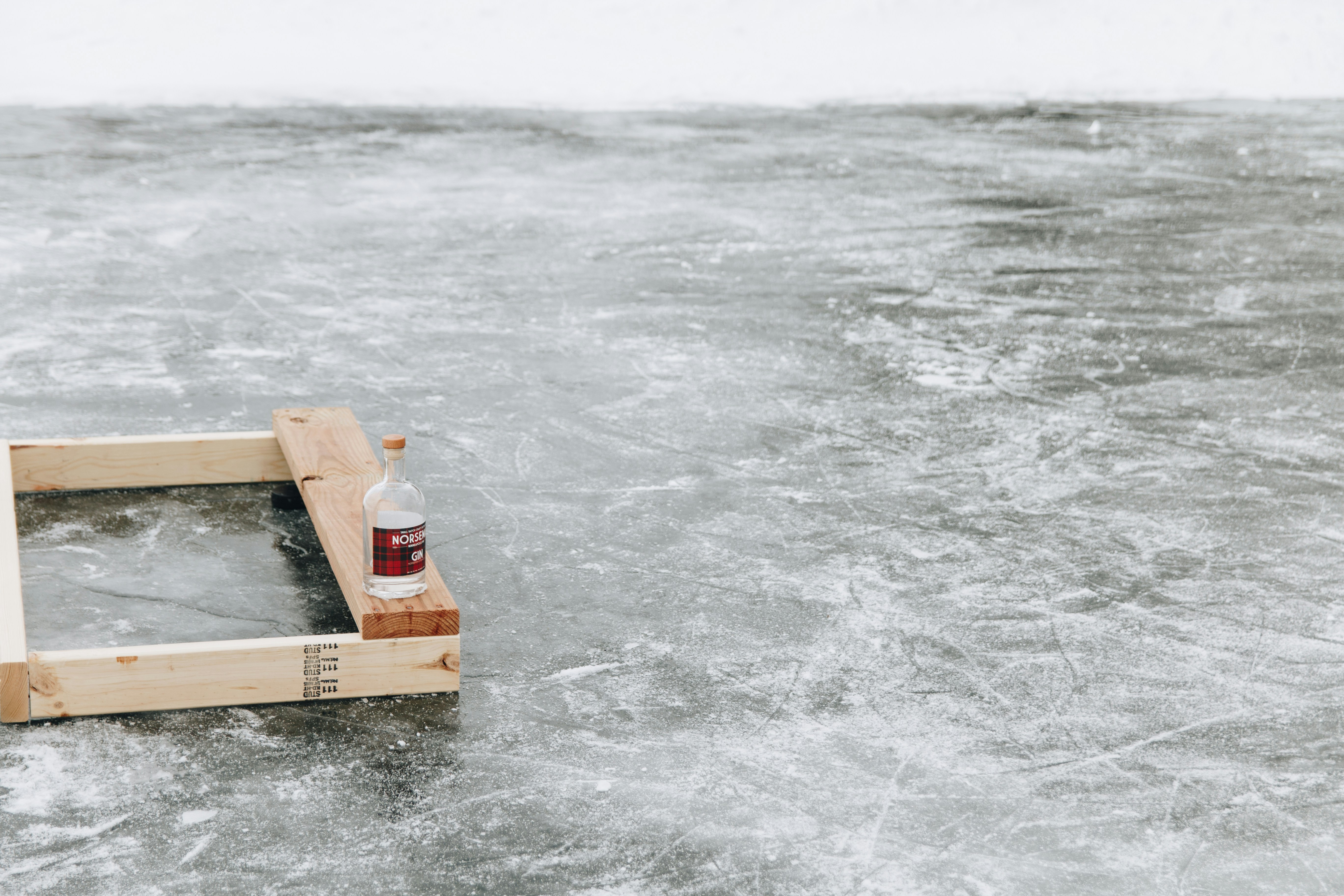 A lone bottle on a wooden frame rests on a barren icy expanse