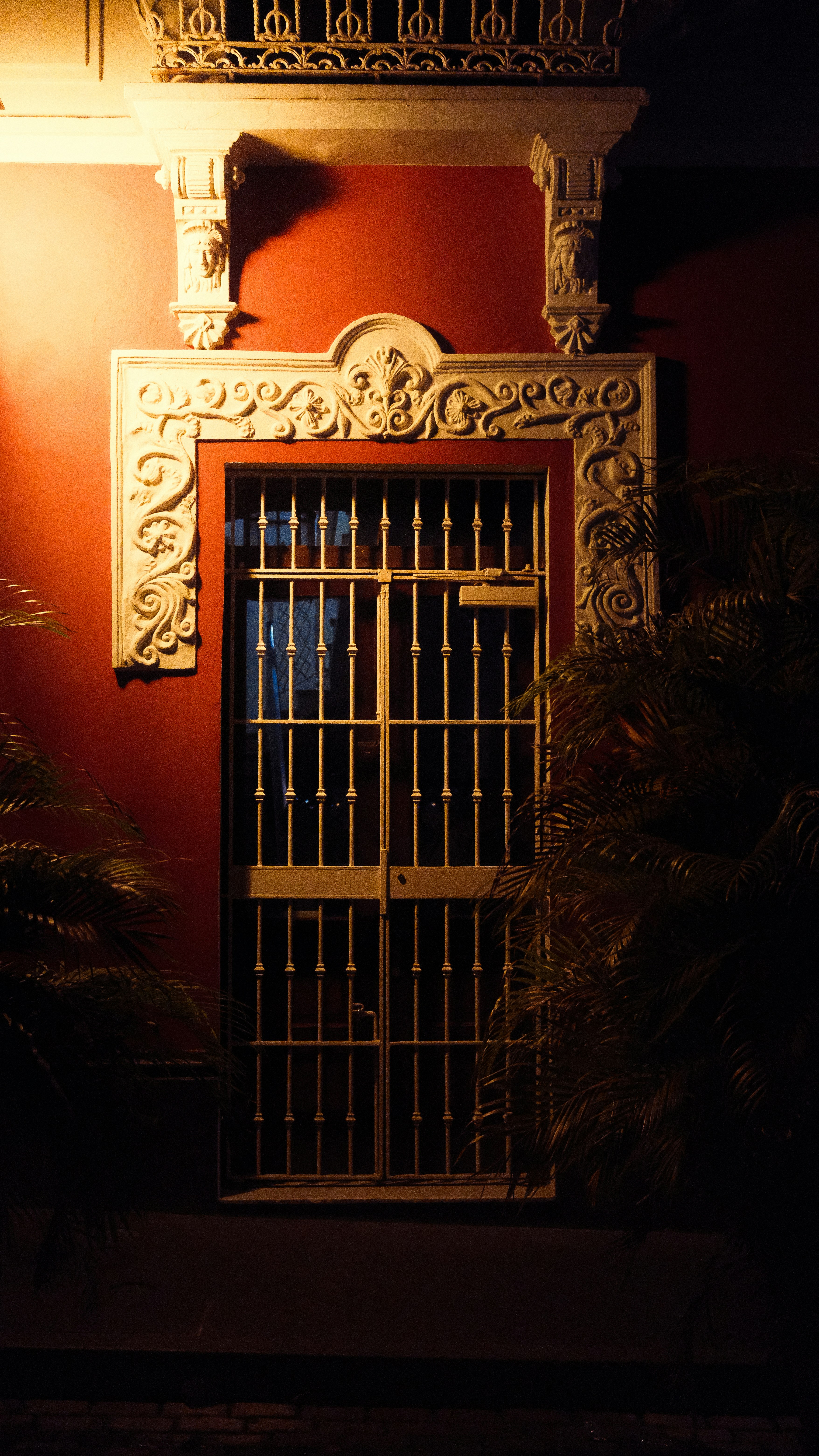 Gate of Ornament: Night Shot of a Red Facade and Barred Door