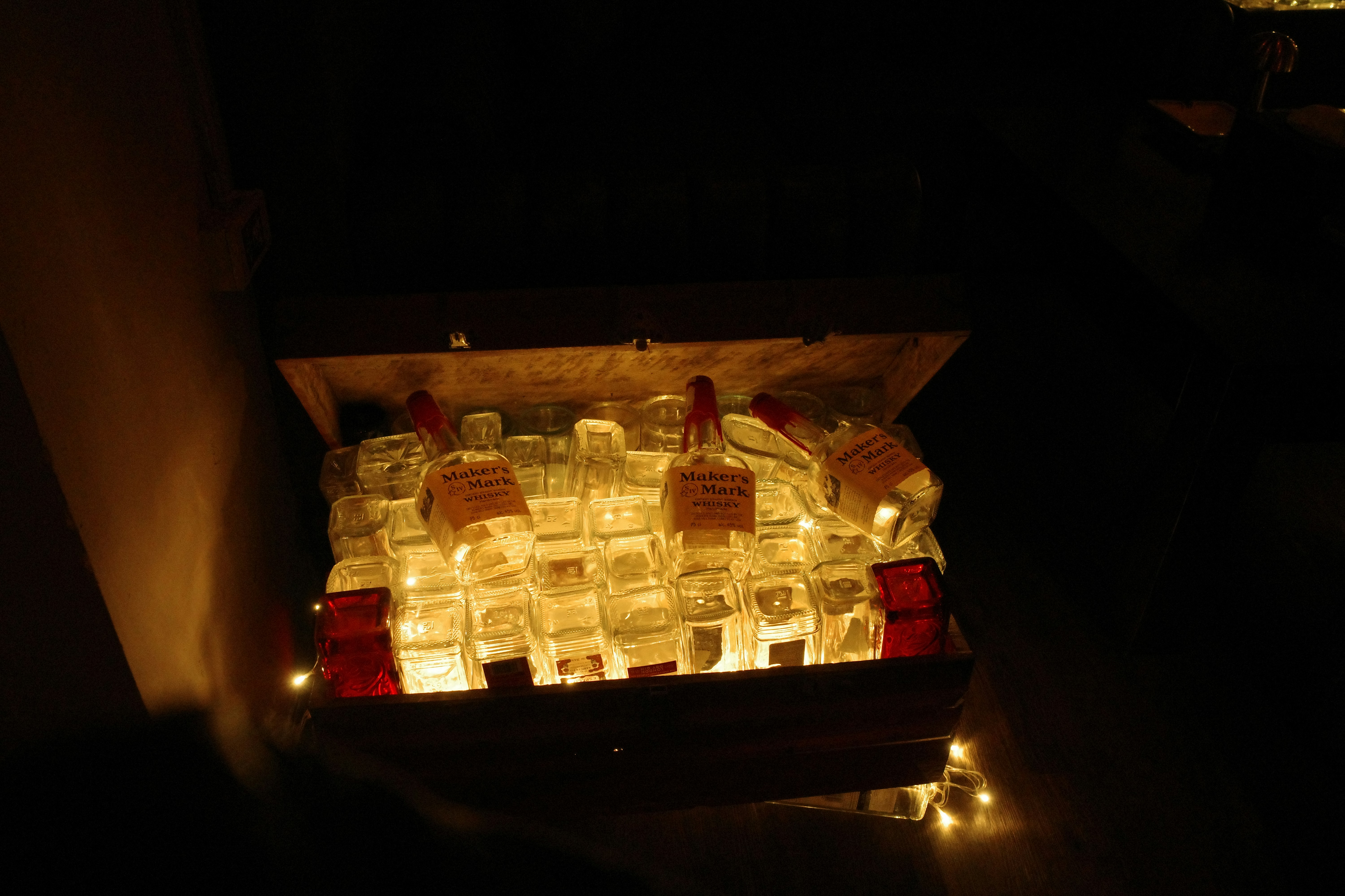 A lighted display of bottles and candles in a dark room