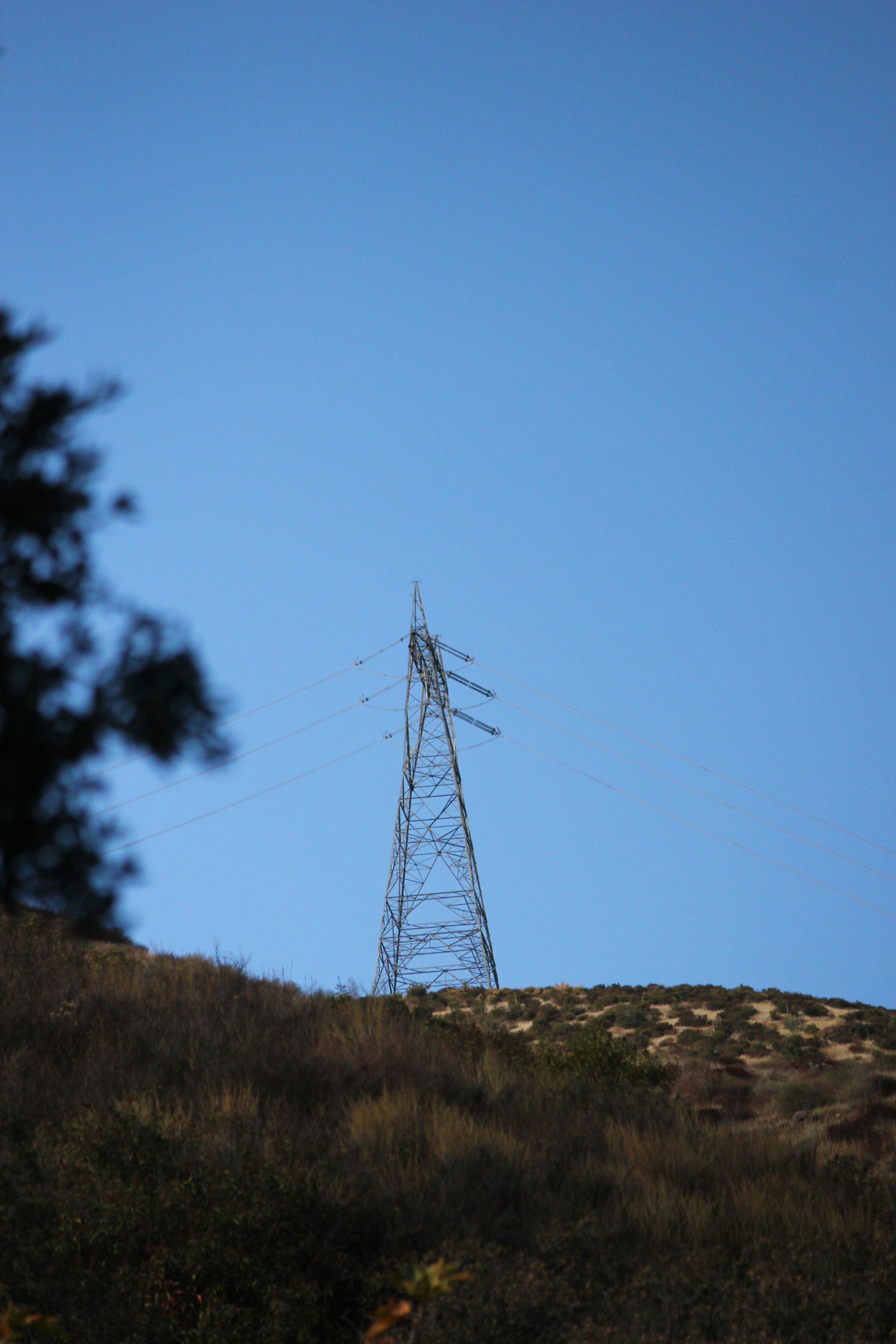 Lattice Peak Against a Clear Azure Sky: A Lone Transmission Tower on the Ridge