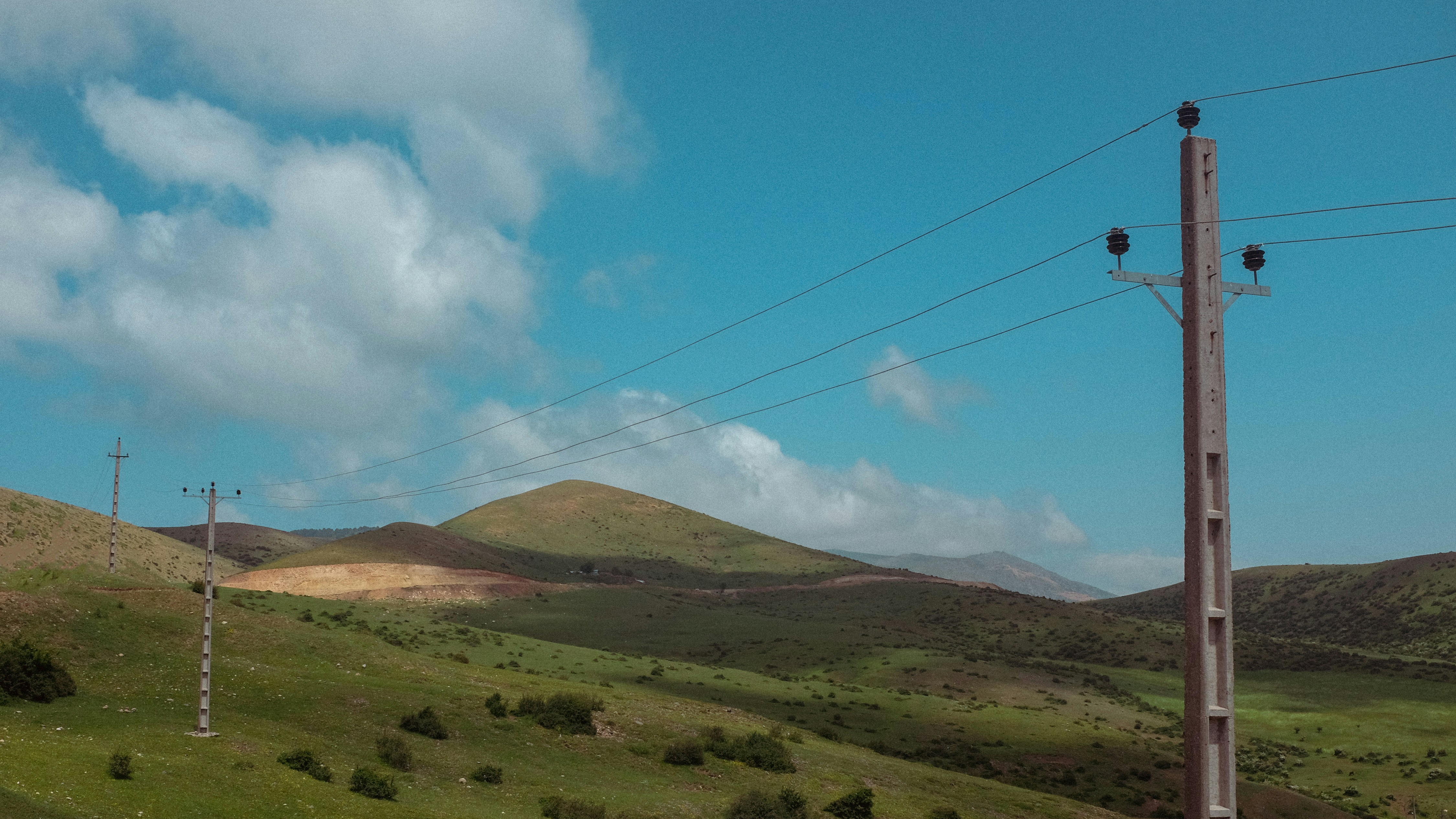 A set of utility poles with perspective view, a sunny sky with bright clouds.