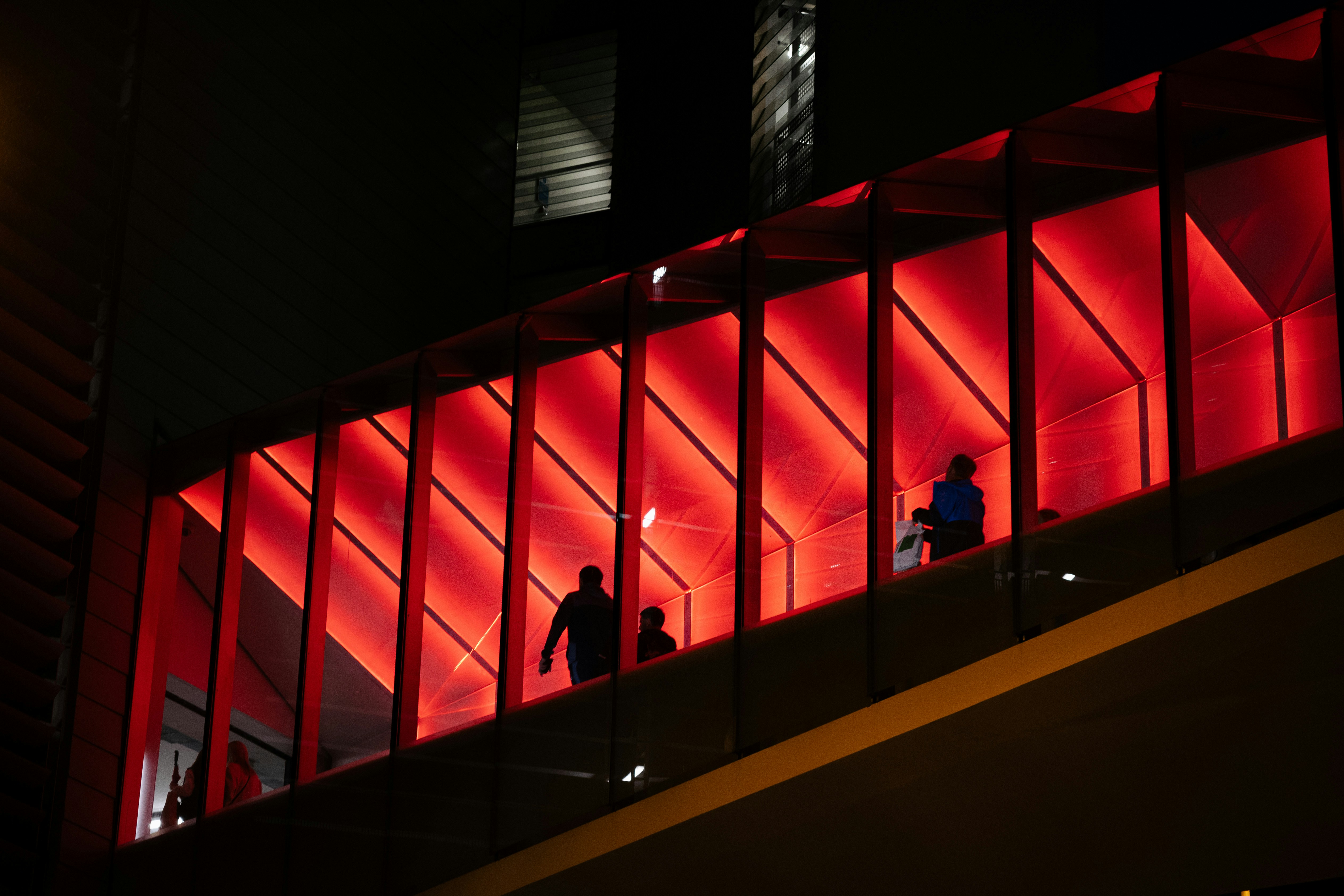 Neon Tram Crossing: A Strut of Red Light and Quiet Figures