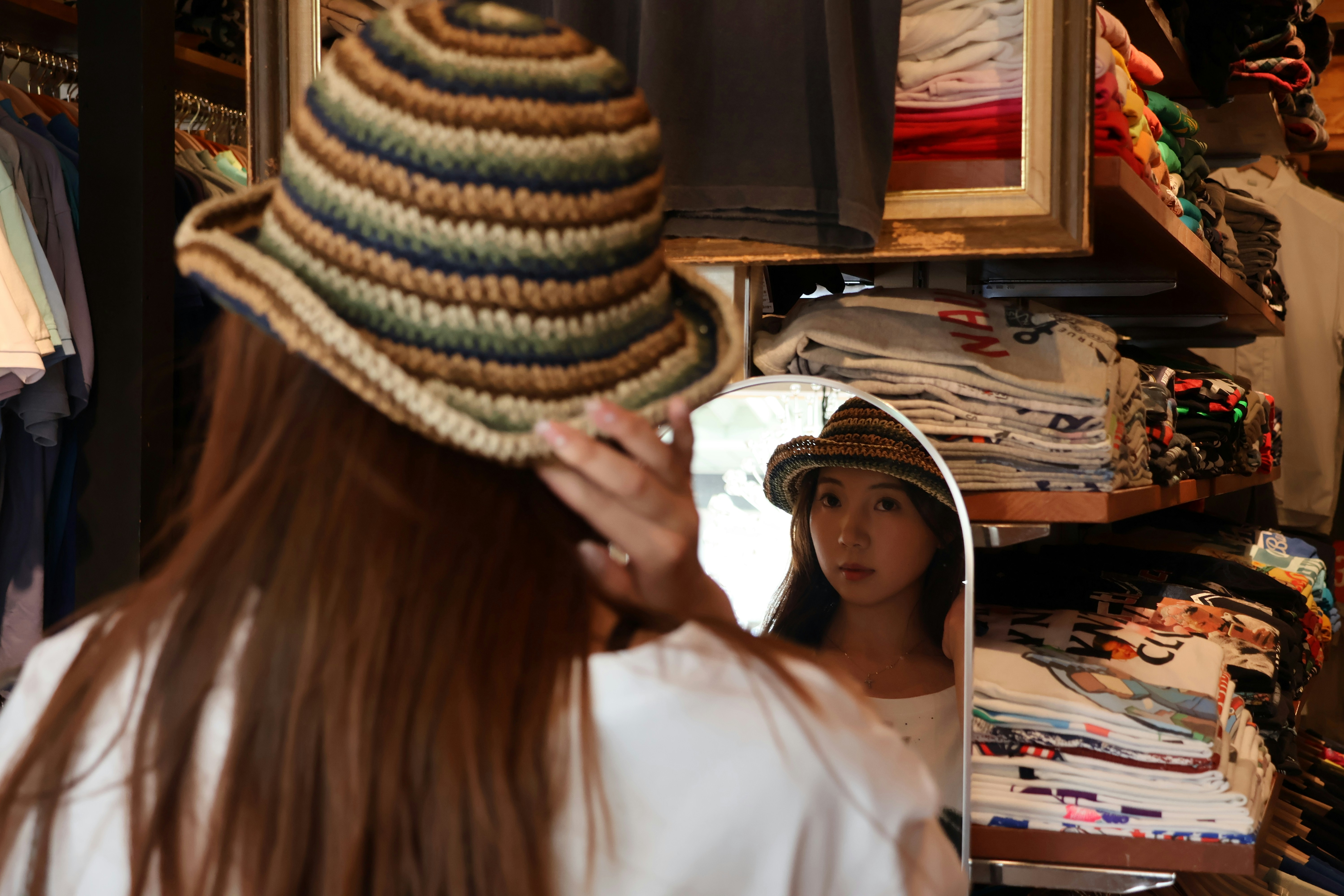 A woman standing in front of a mirror with a hat on her head