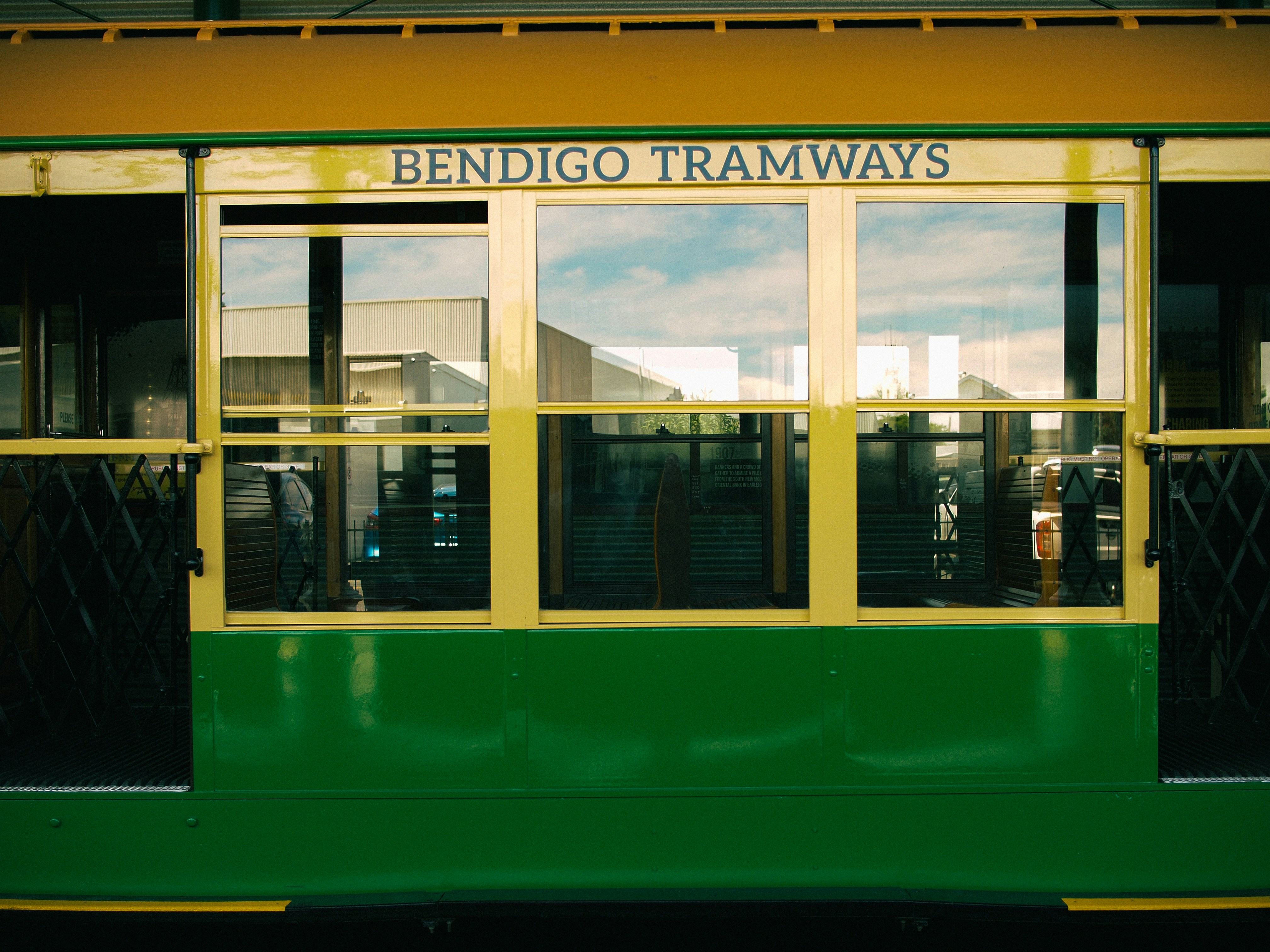 A green and yellow train car sitting on the tracks