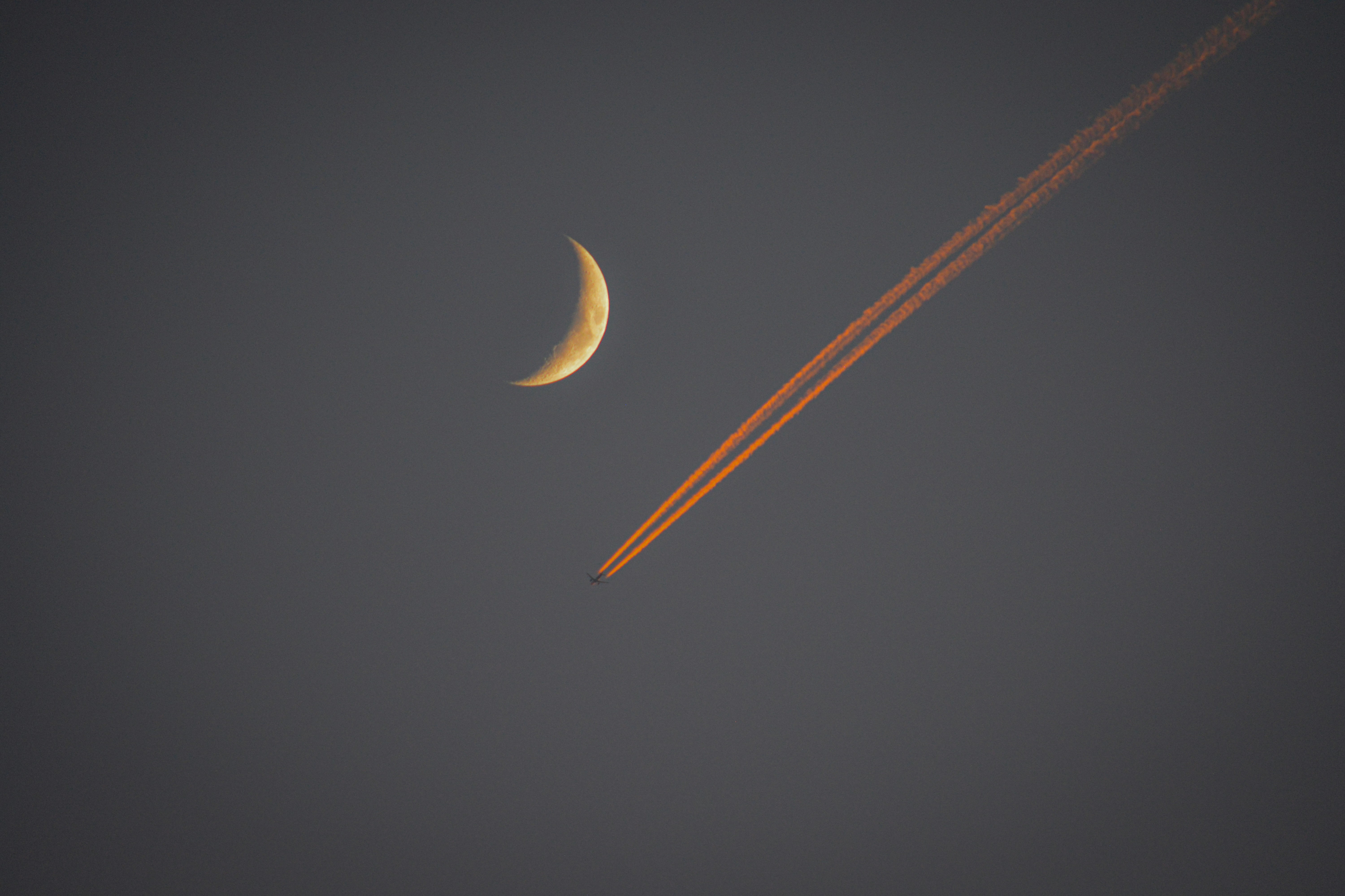 Crescent Moon and Dual Contrails Crossing a Quiet Sky