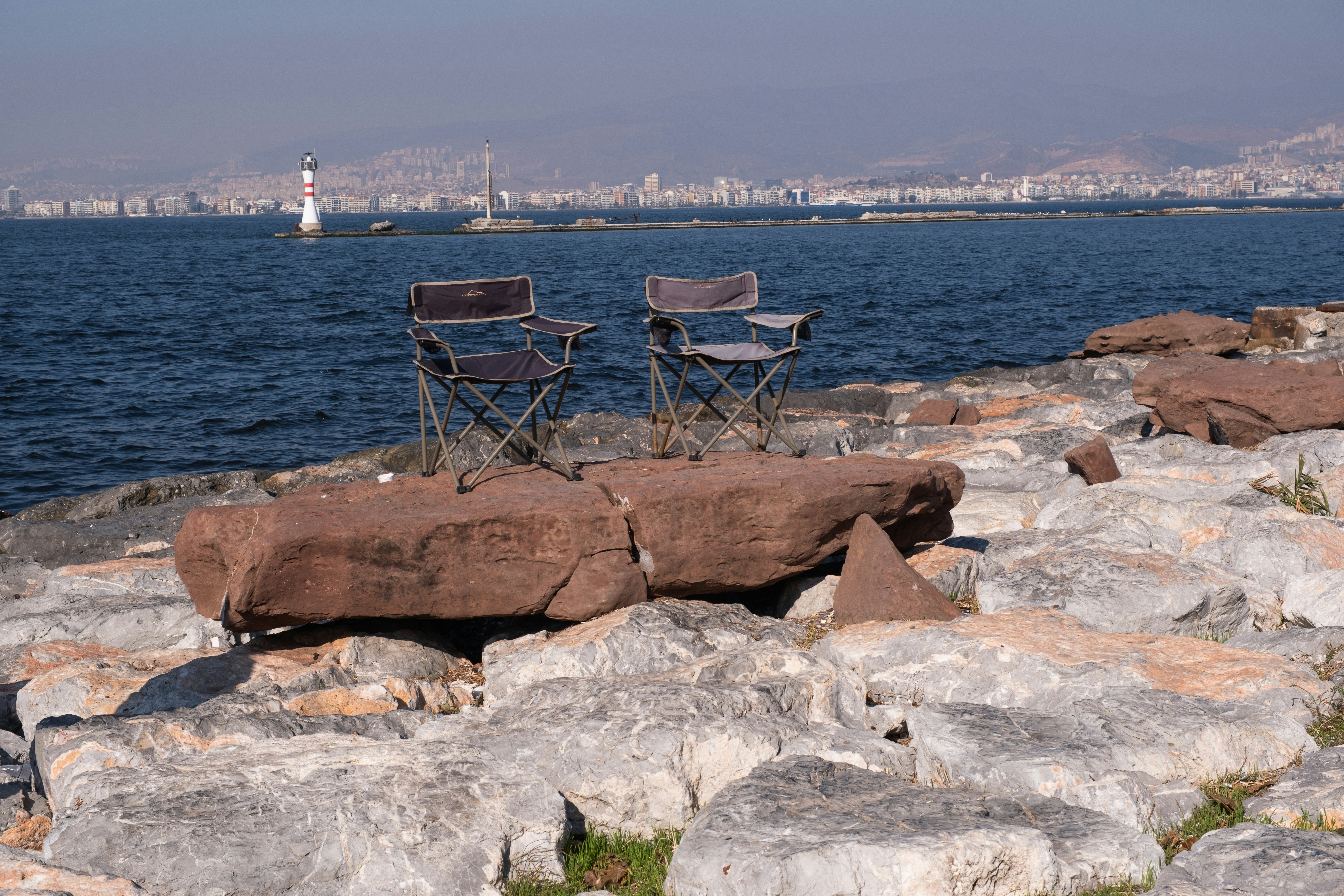 A couple of chairs sitting on top of a rocky shore