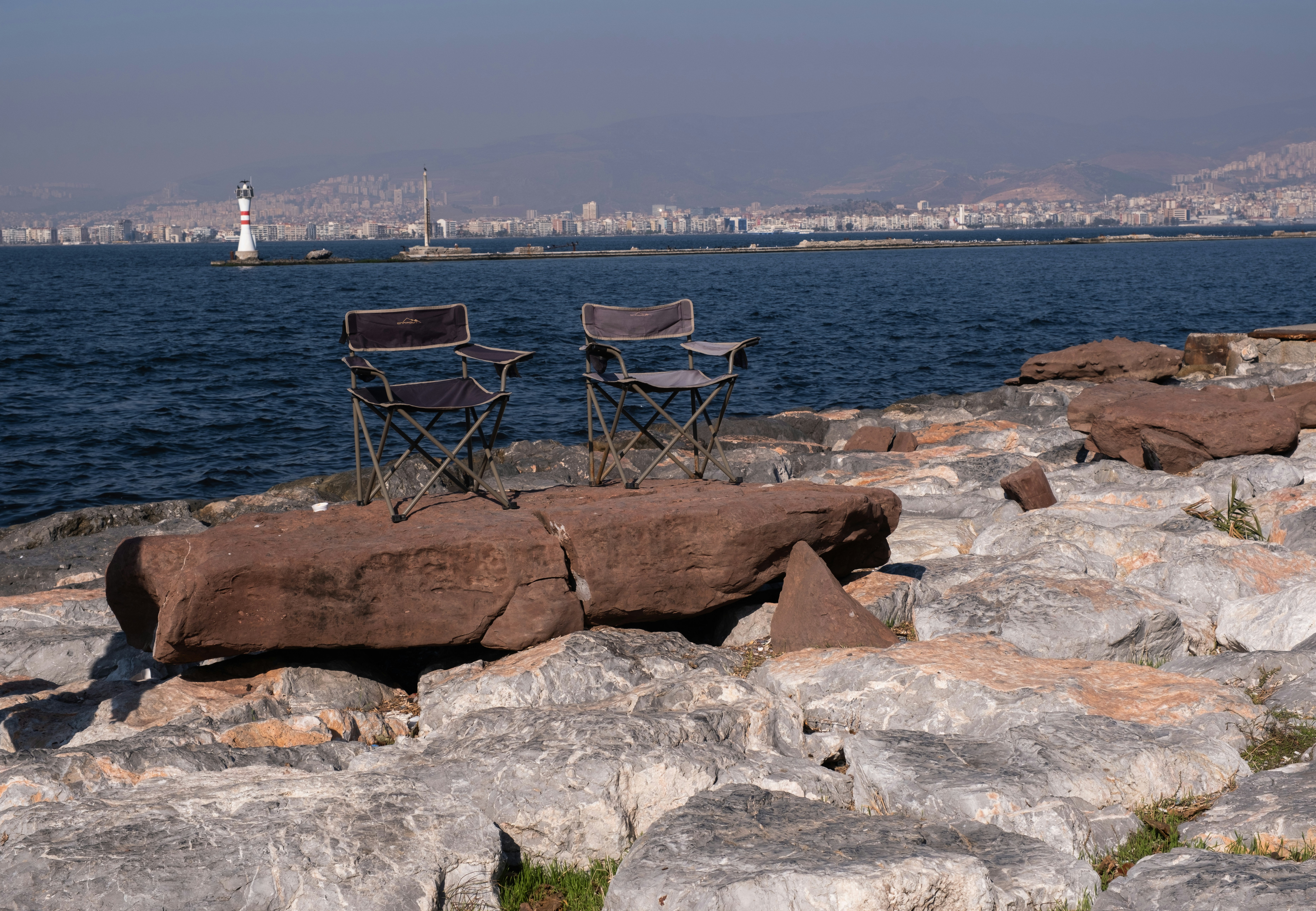 A couple of chairs sitting on top of a rocky shore