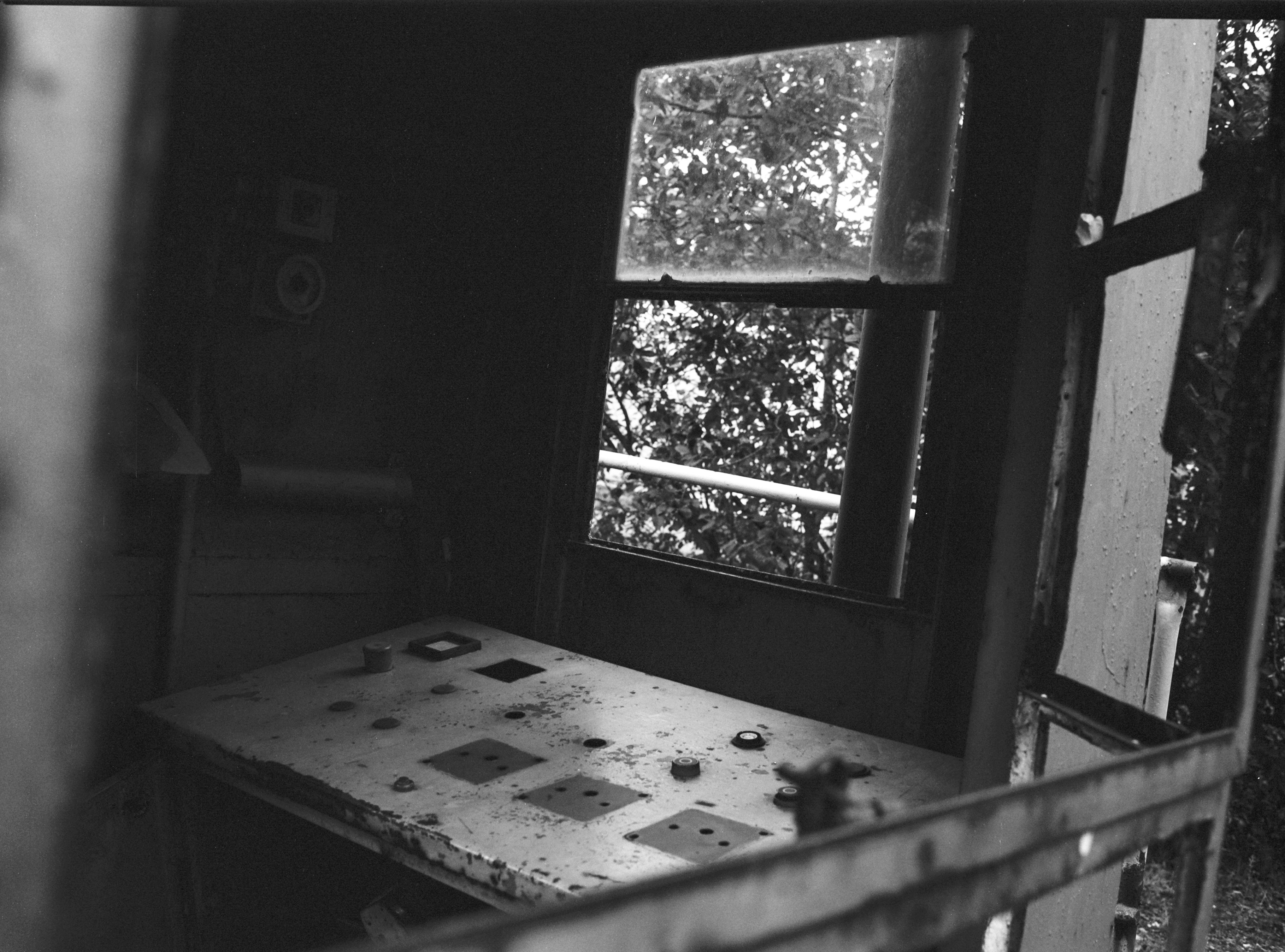 Dust-Covered Console Beneath a Window Framed by Outdoor Light