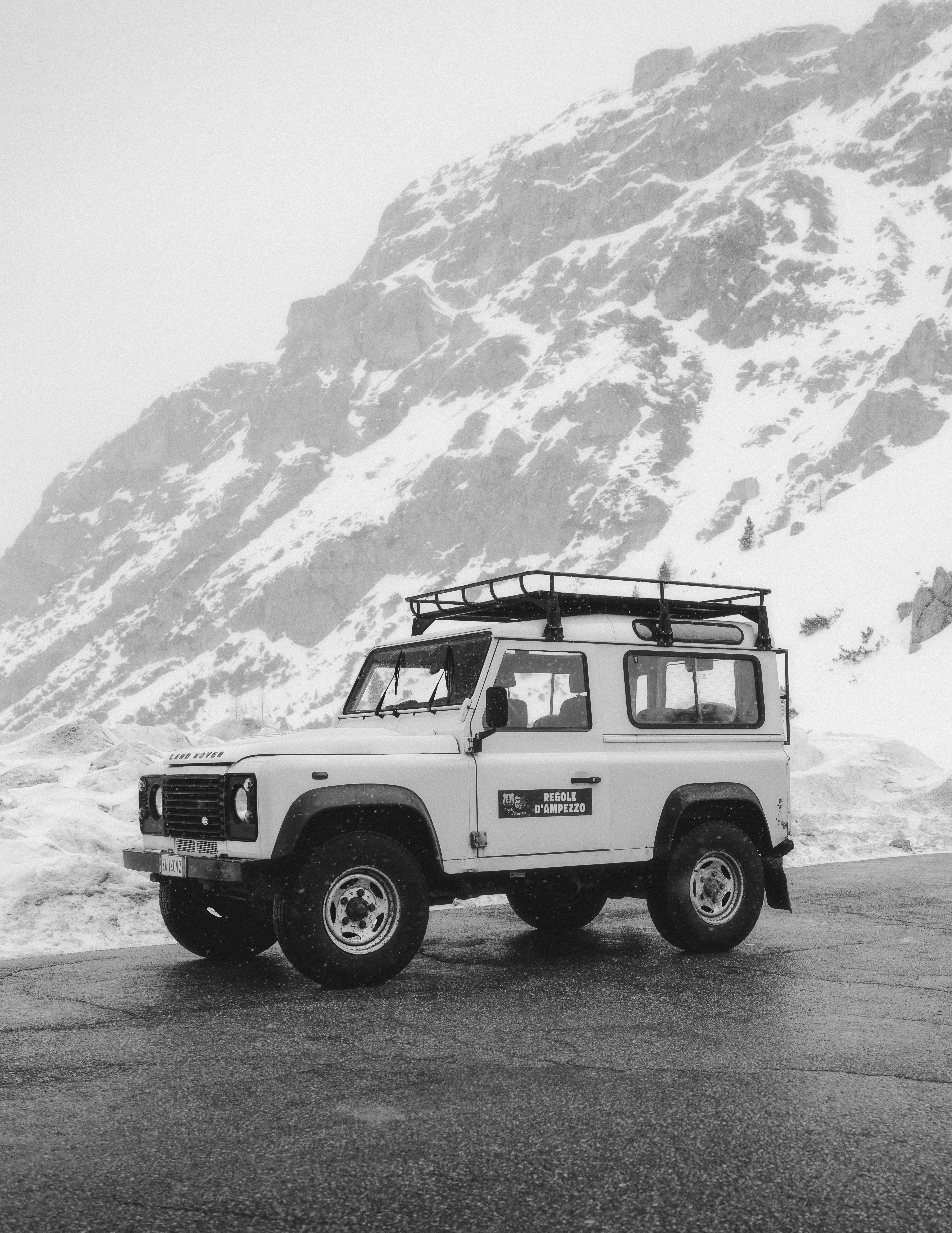 Grayscale Guardian: A Land Rover on a Snow-Dusted Alpine Pass