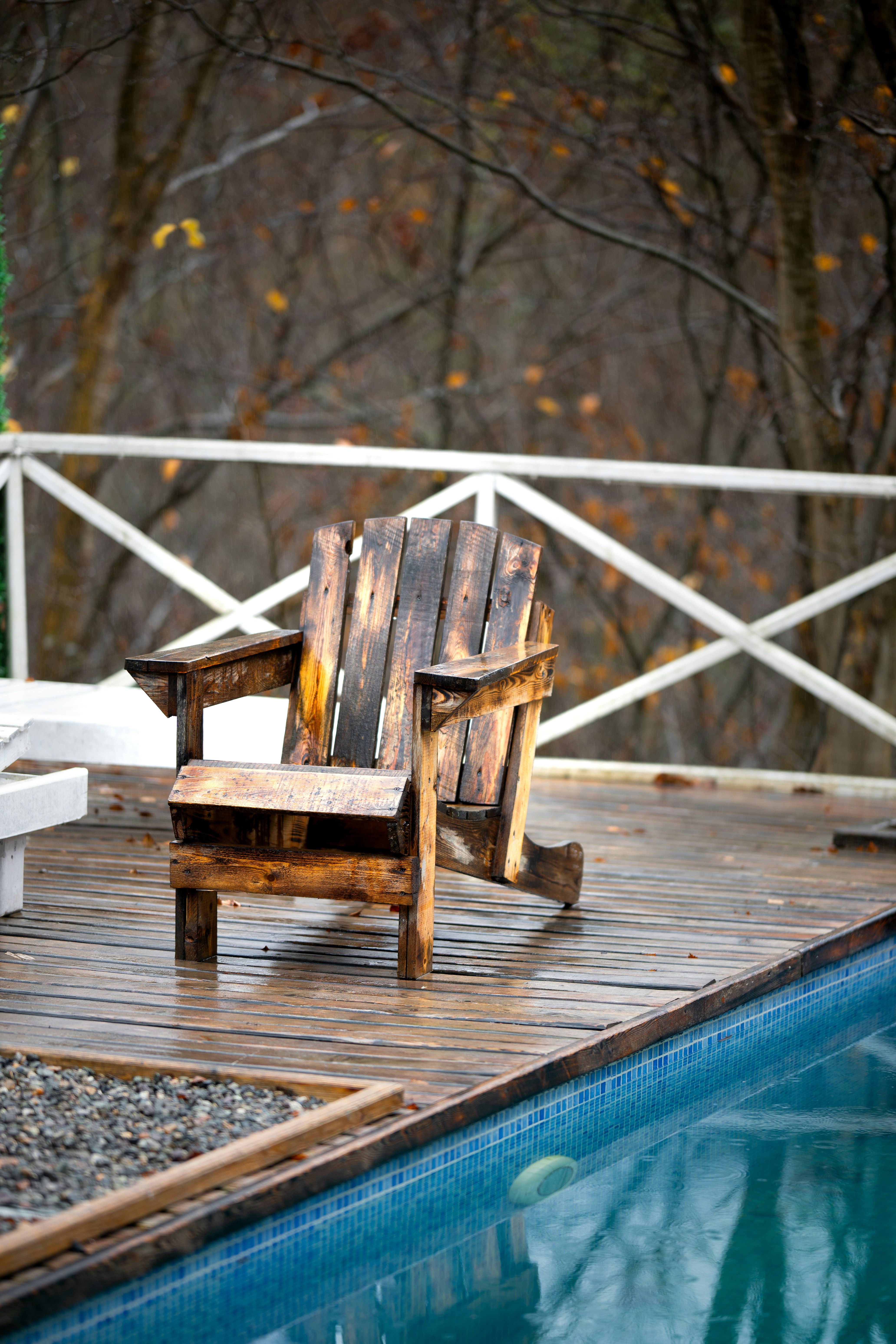 Weathered Wooden Chair by a Rain-Washed Deck: Quiet Poolside Pause with Autumn Backdrop