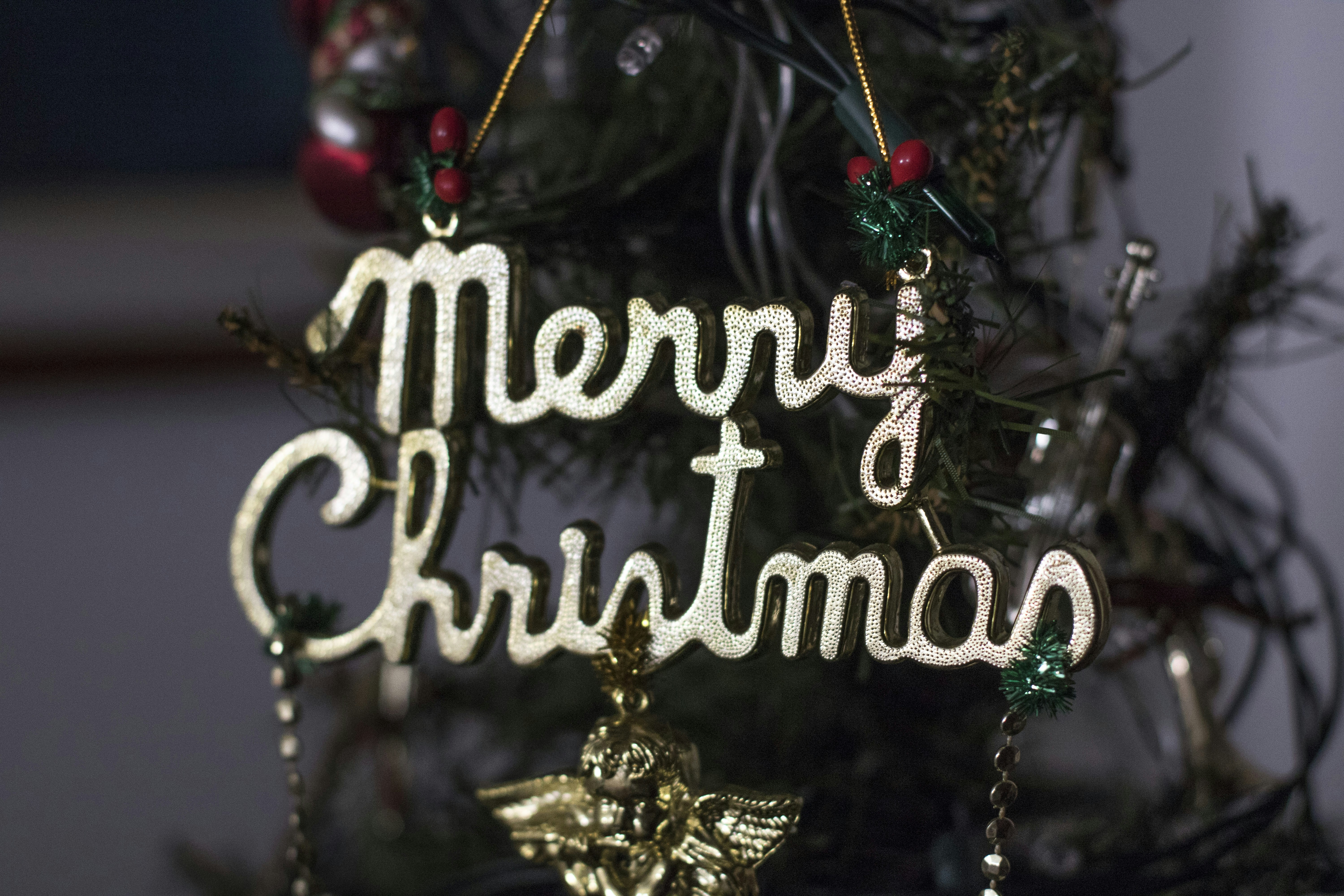 Gold Script Ornament Nestled Among Dim Christmas Tree Lights