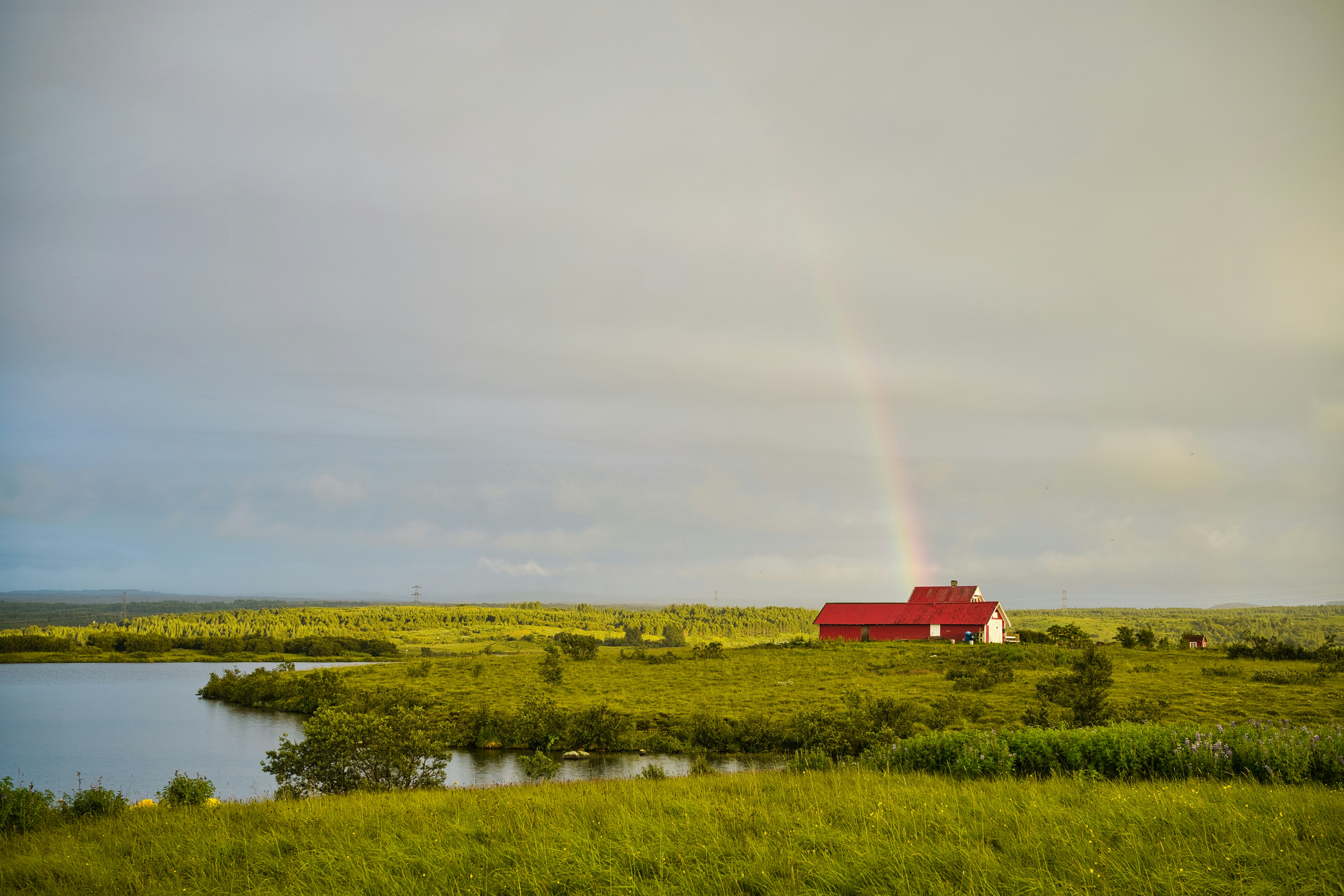 Red Barn under a Gentle Rainbow Over Prairie Waters