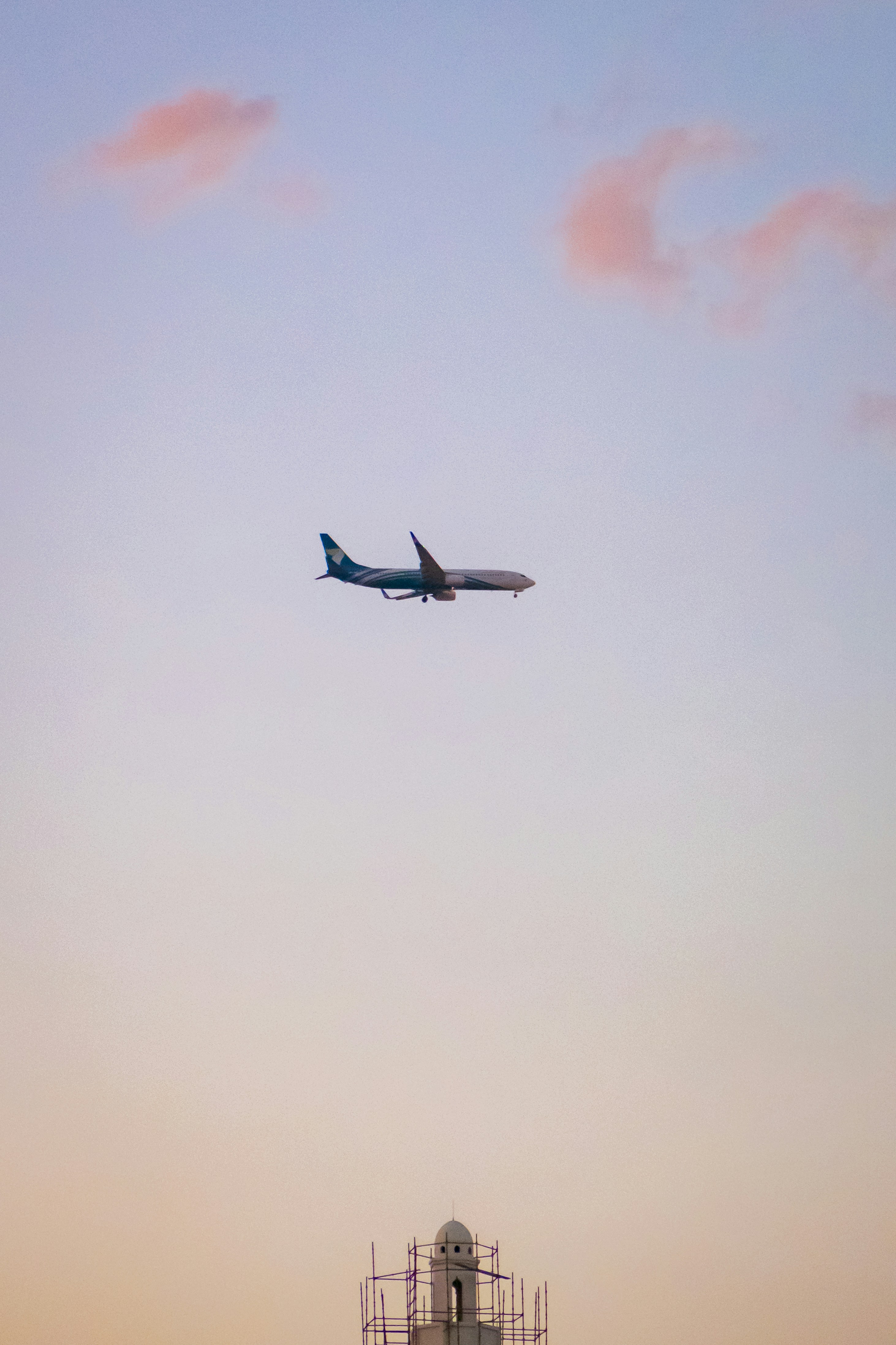 Vessel in Transit: A lone airliner gliding above a distant tower at dusk