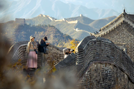 Three Travelers and a Dog Pause on the Great Wall Beneath Mountain Backdrop