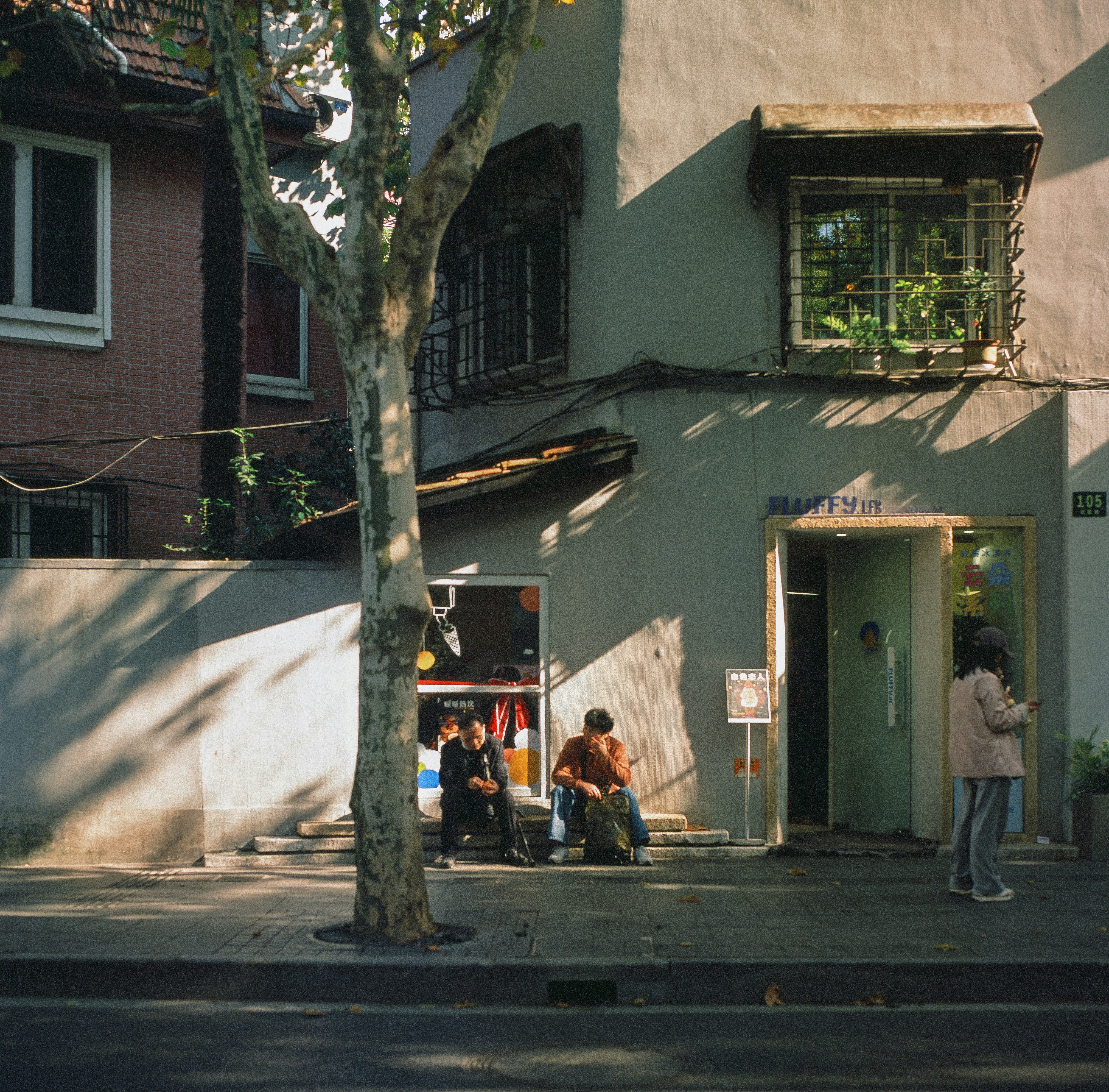 A group of people sitting outside of a building photo – Free Street ...