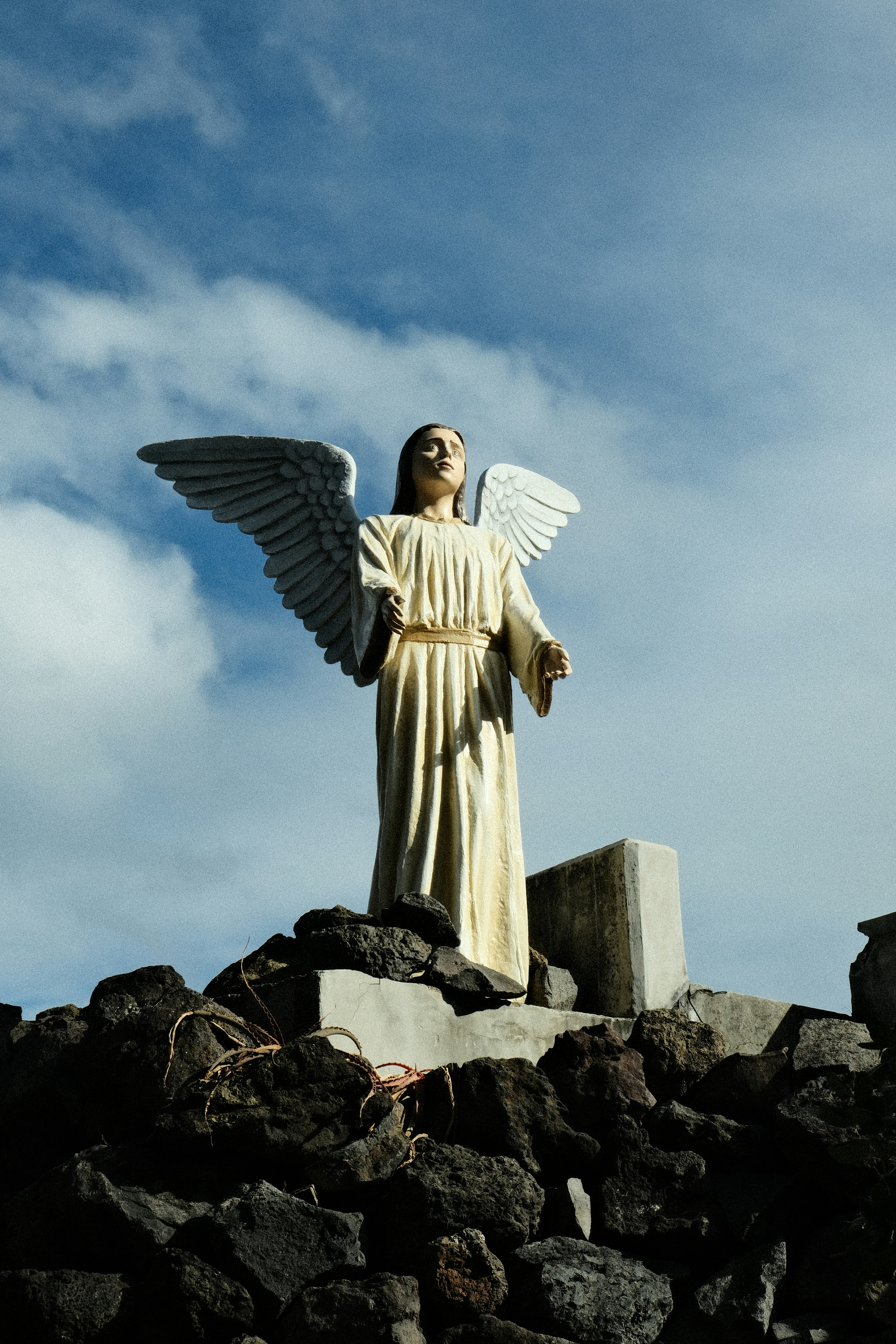 Winged Guardian on the Crag: A Solemn Statue Reigning Over Jagged Stones