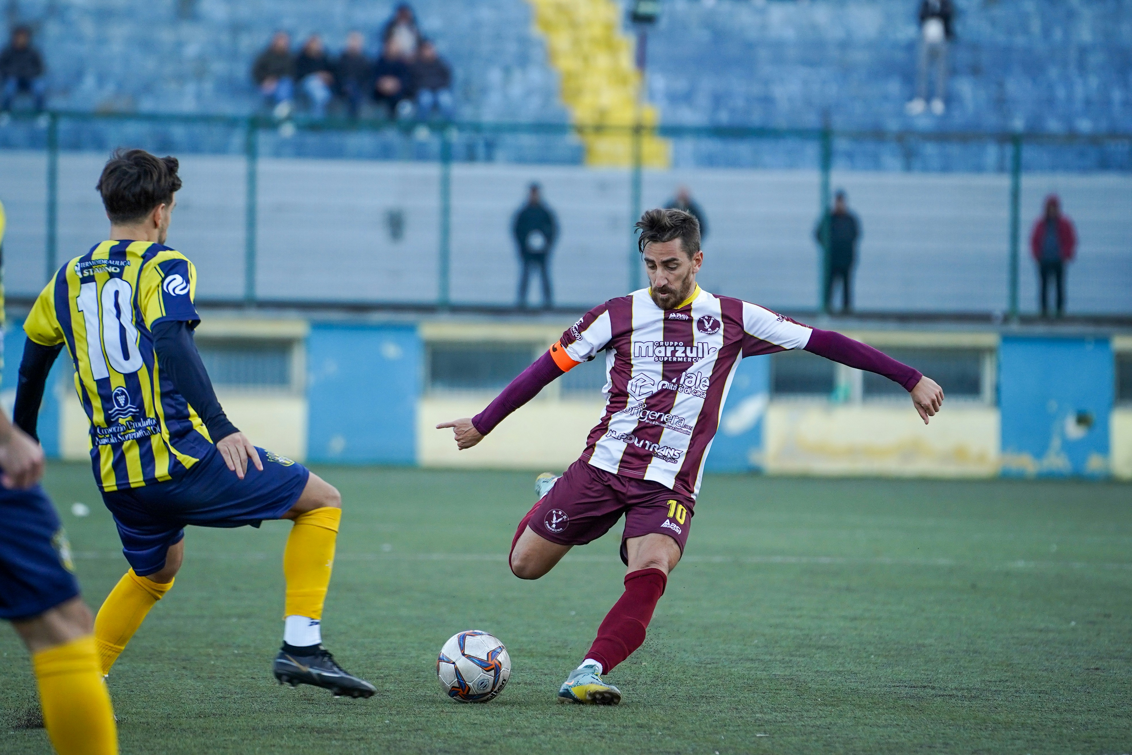 Young soccer player in red and white uniform about to kick the ball during a match on a grass field.