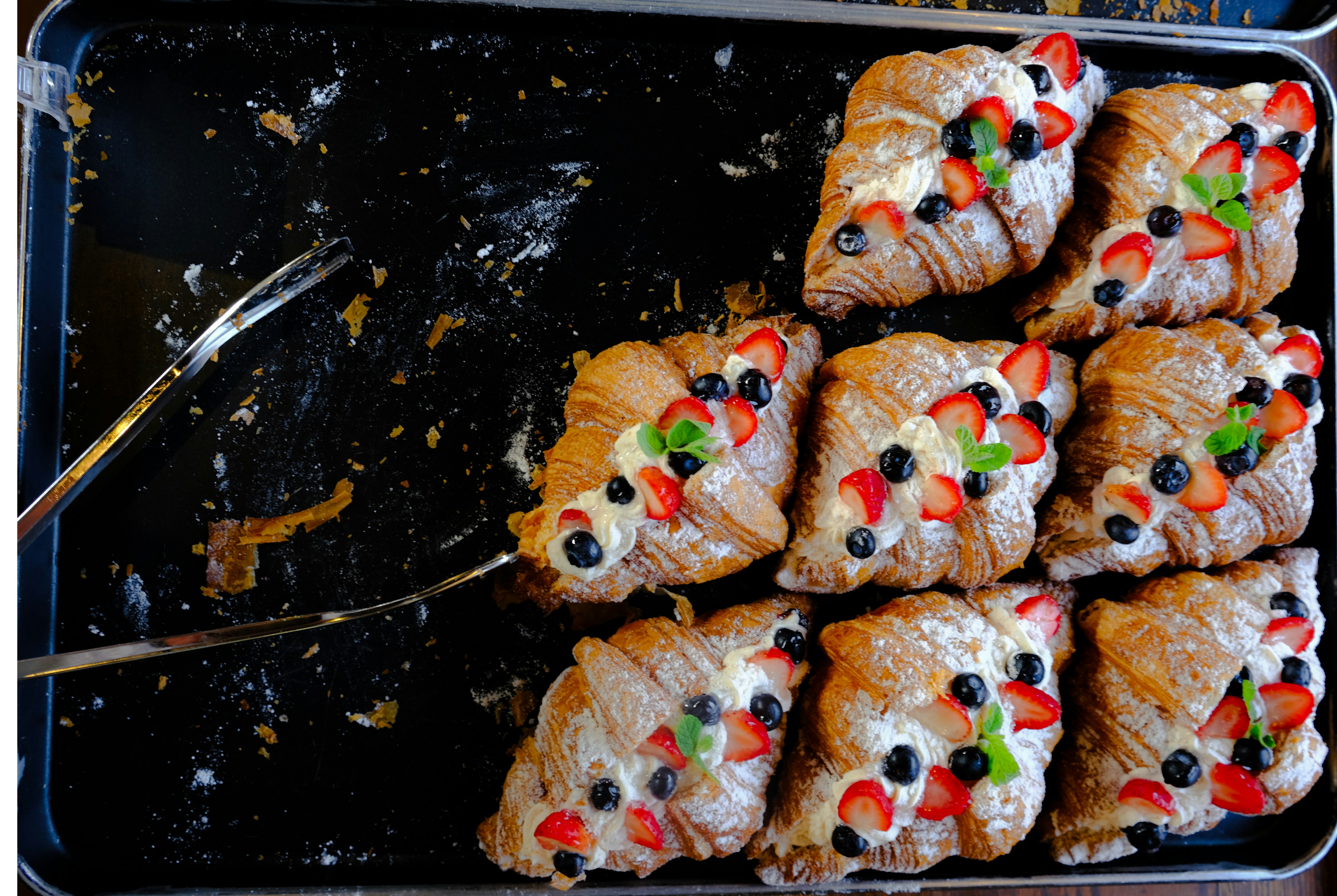 Berry-Topped Crescent Pastries Adorning a Dark Baking Tray
