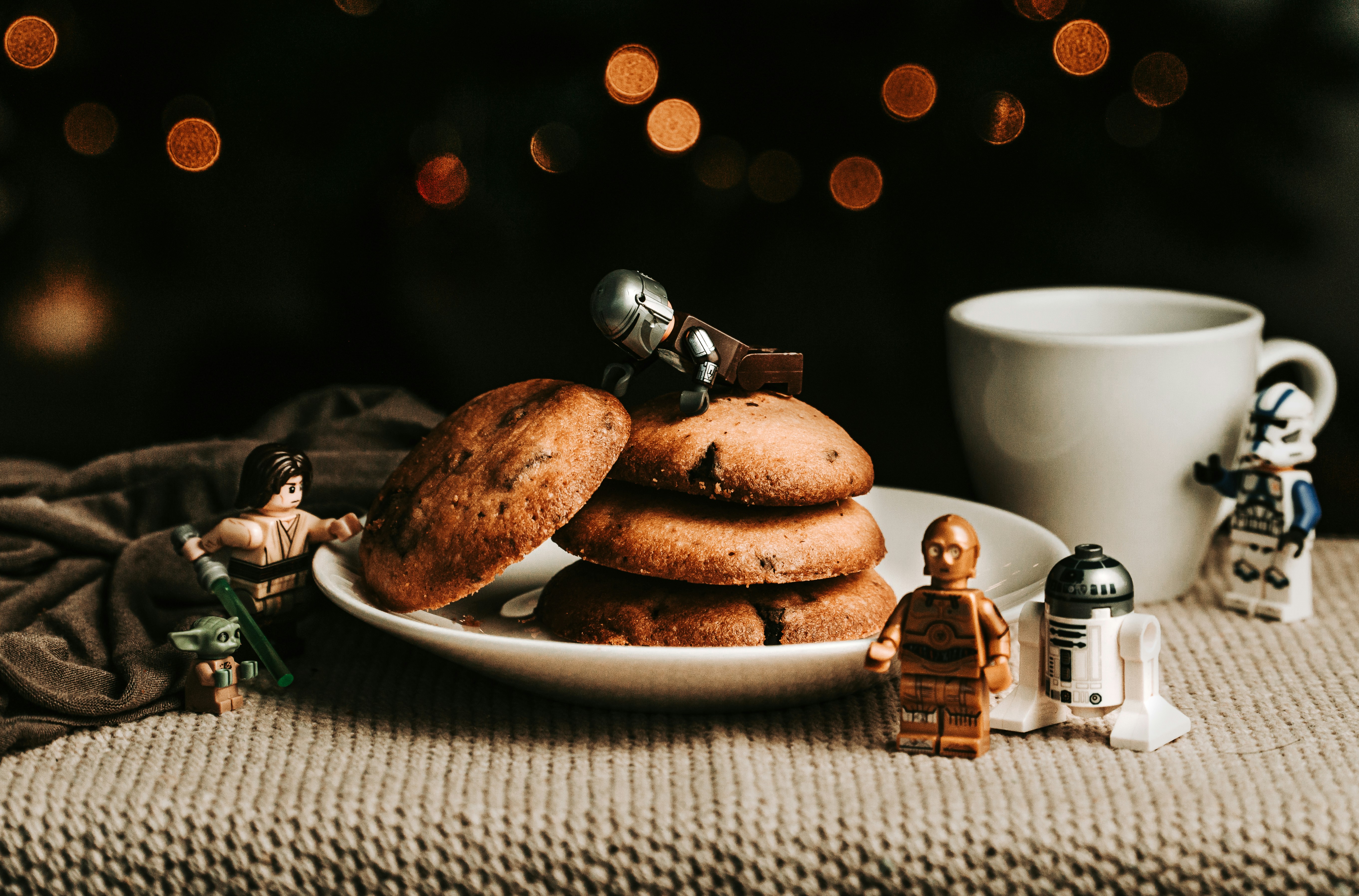 Tiny LEGO Guests Perch on a Cookie Stack Beneath Warm Bokeh