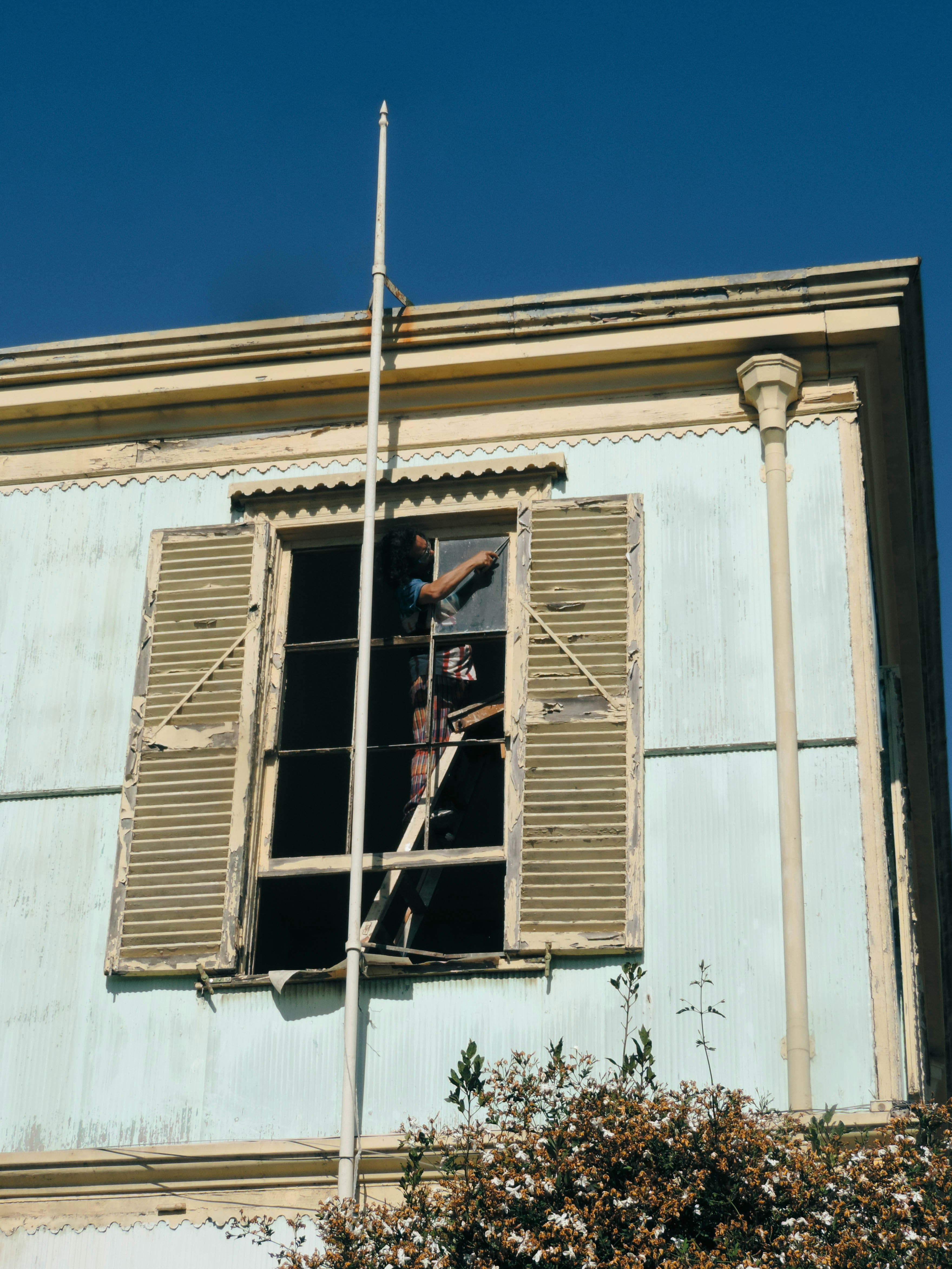 Window Watcher: A Balcony Window Veil of Rust and Blue