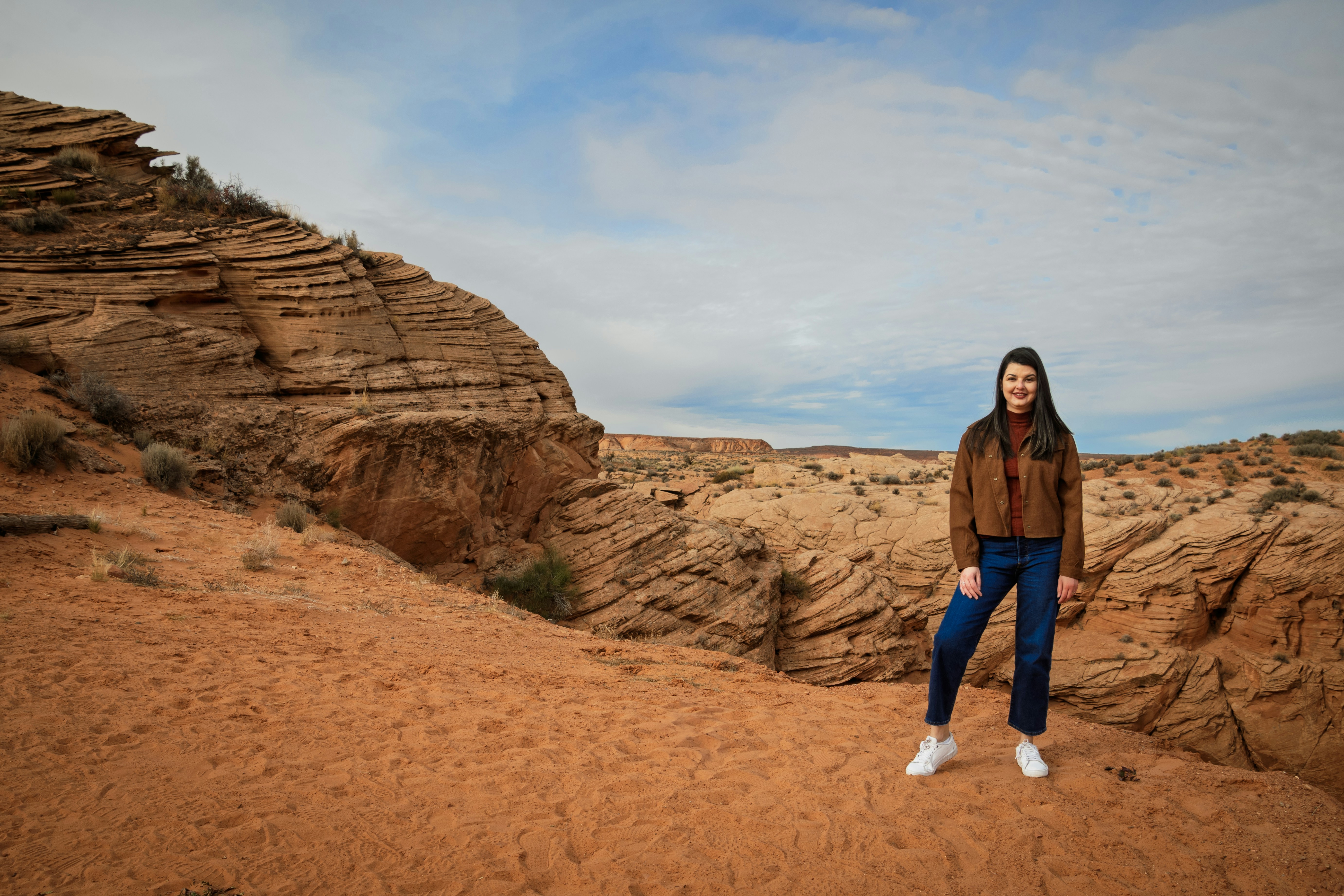 A man standing in a desert area next to a cliff photo – Free Portrait ...