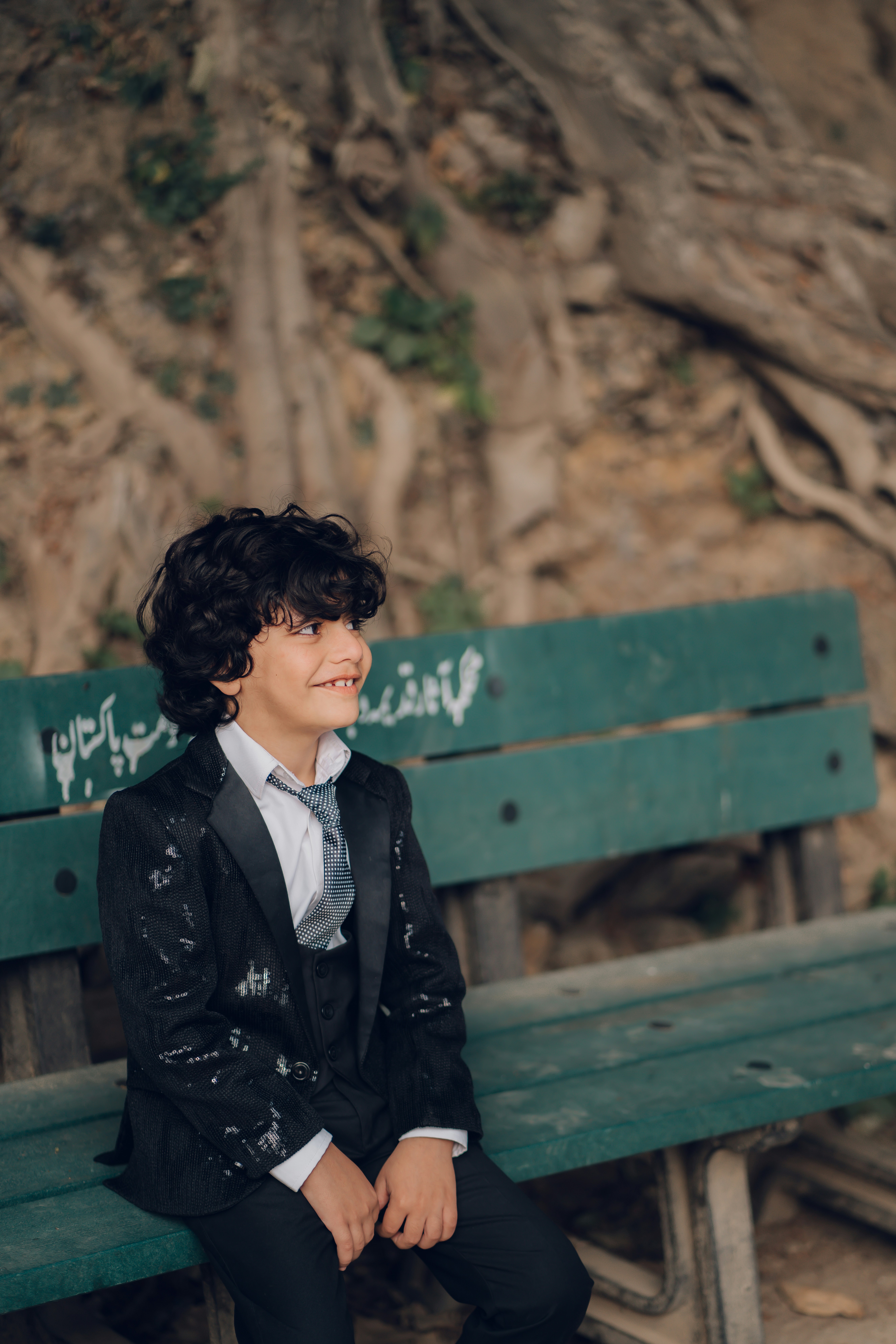 A young man in a tuxedo sitting on a bench